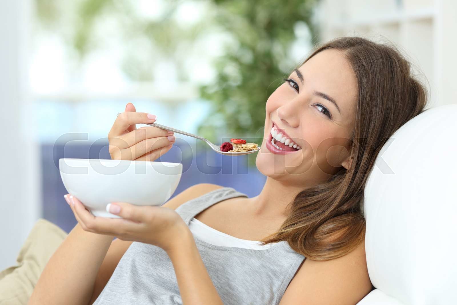 Happy girl eating cereals at home | Stock image | Colourbox