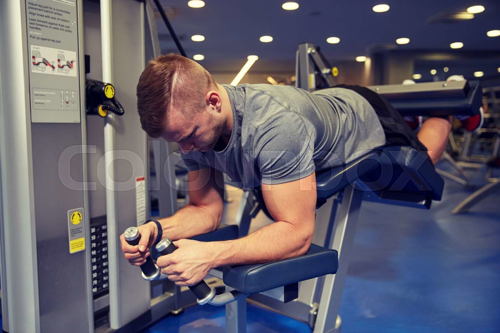 man flexing leg muscles on gym machine | Stock image | Colourbox