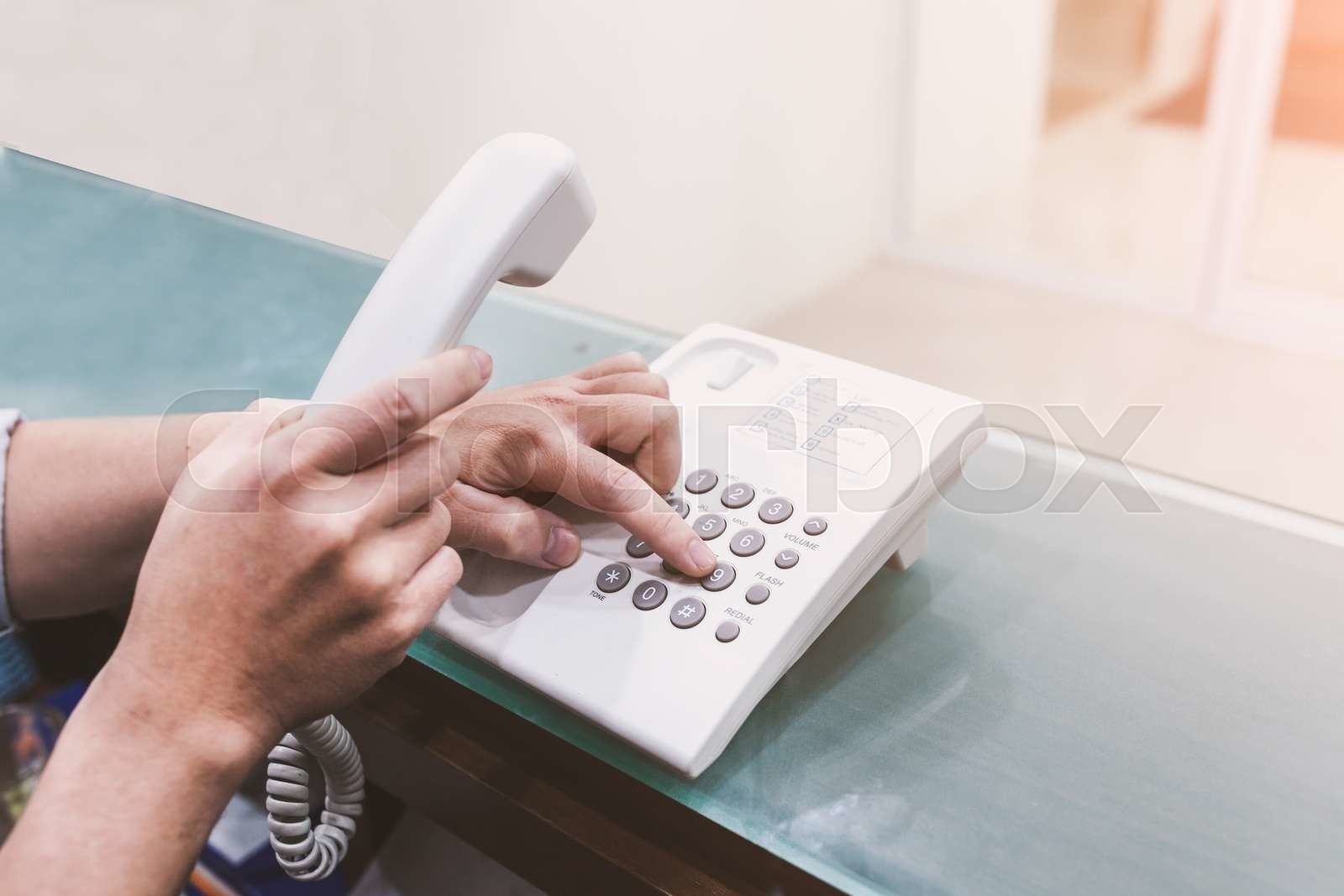 Human hands holding telephone handle and dialing | Stock image | Colourbox