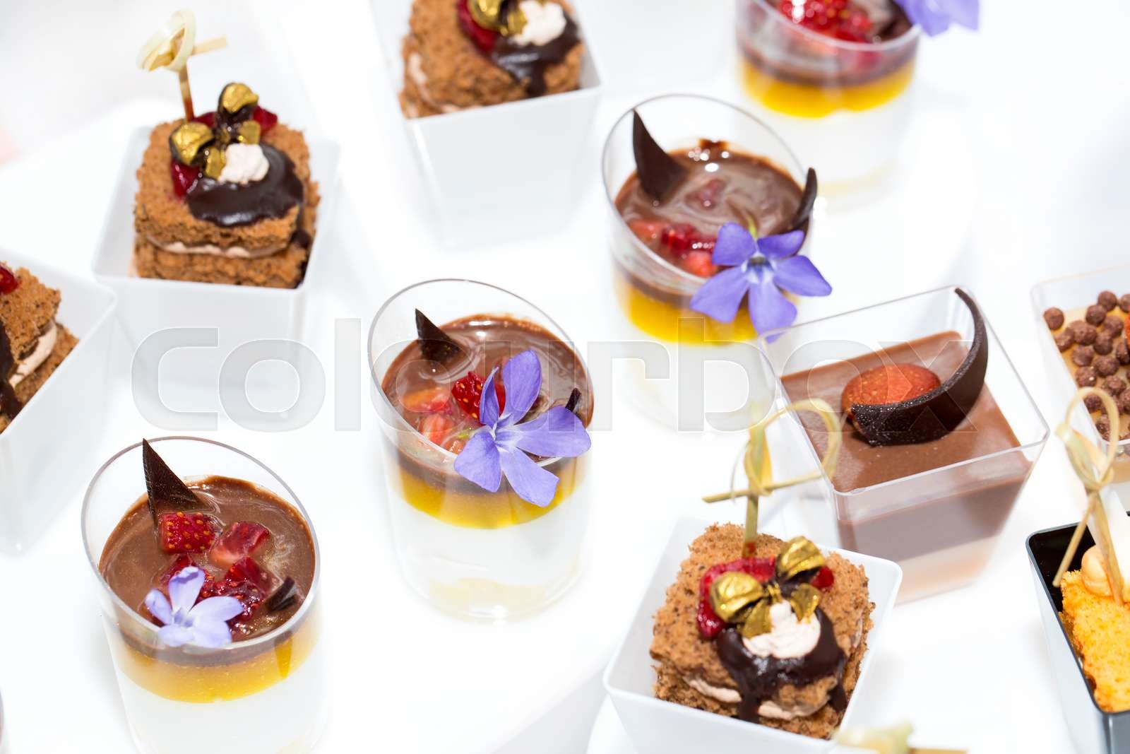 mini canapes in plastic cups decorated with edible flowers | Stock ...