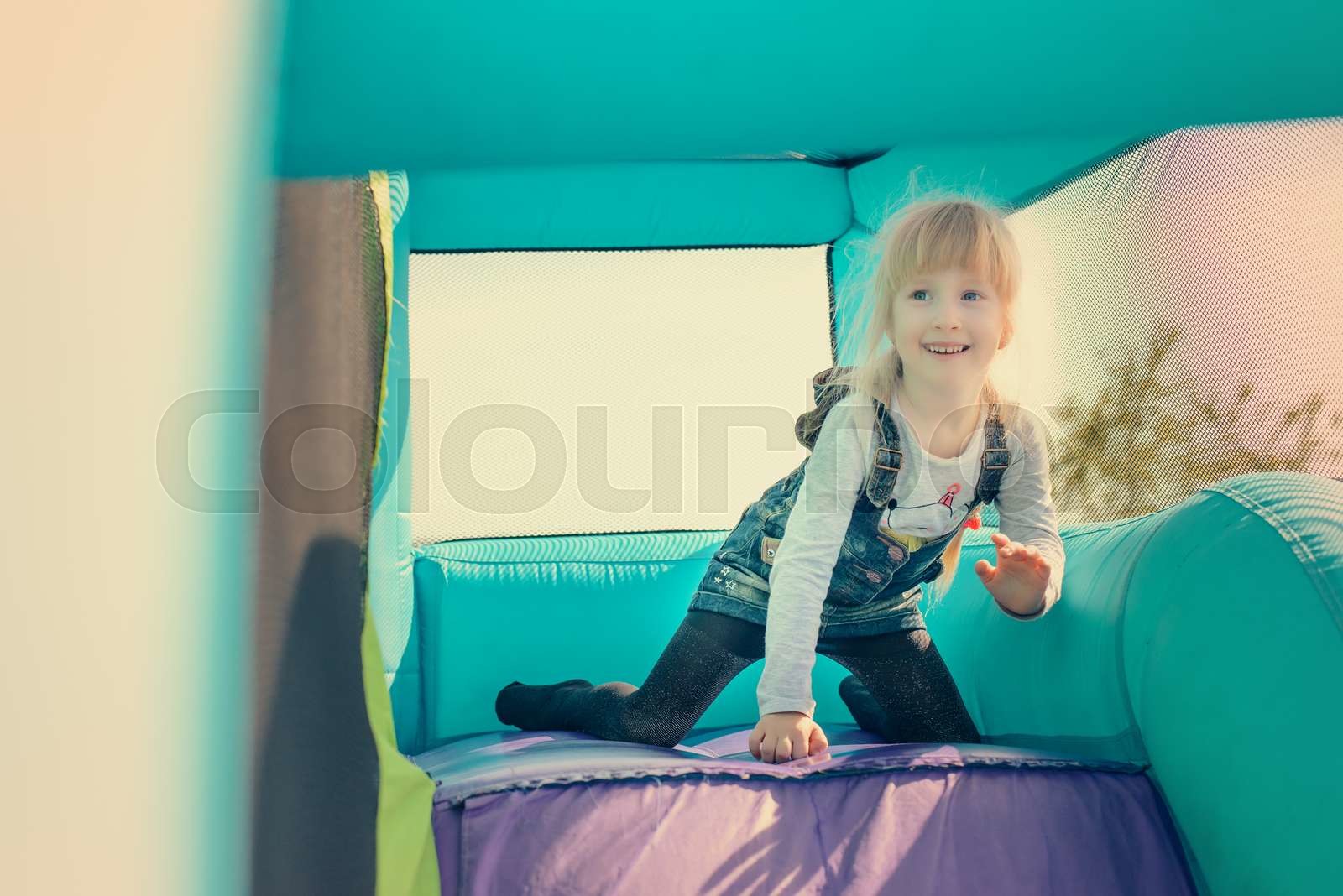 Happy girl going down inflatable slide | Stock image | Colourbox