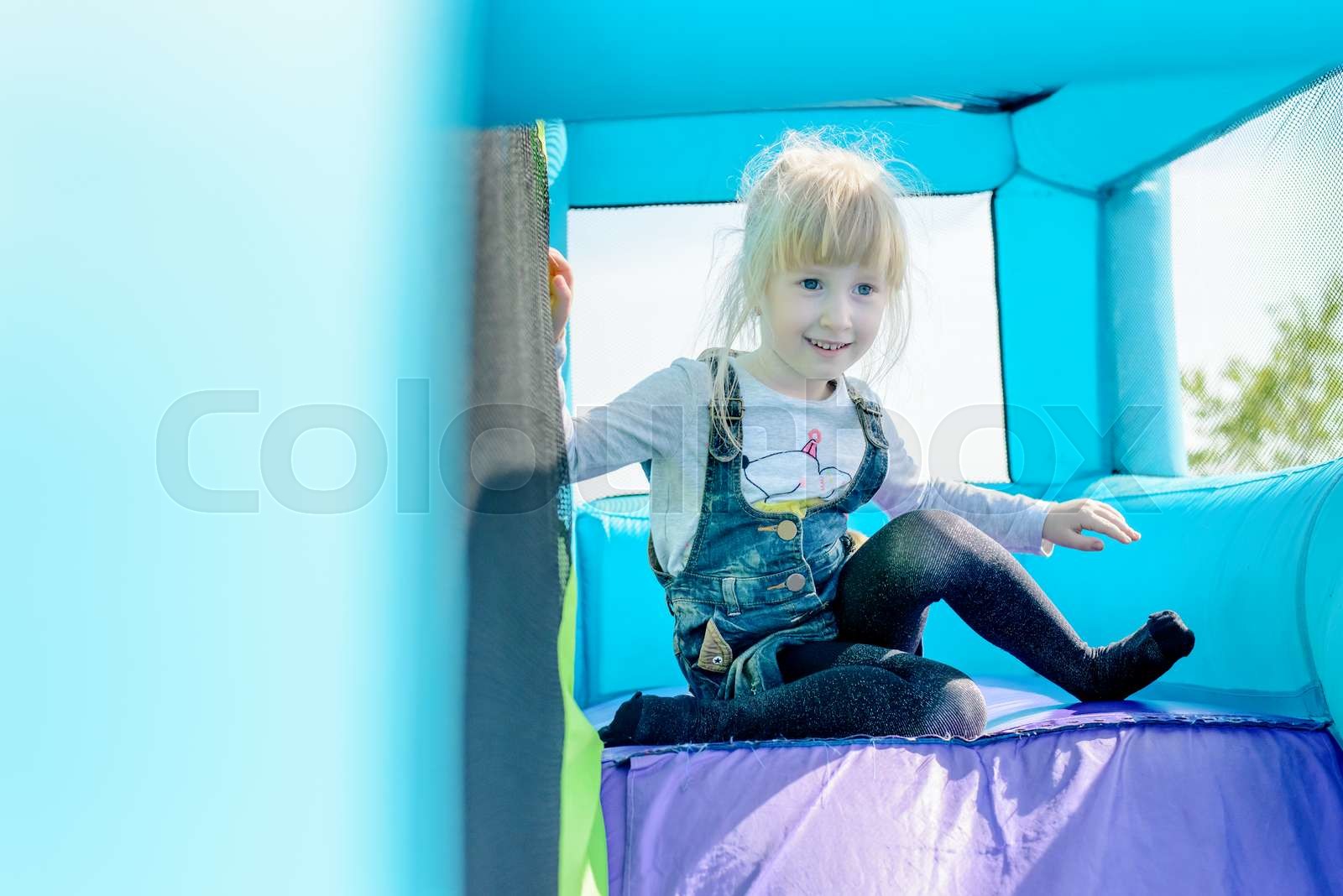 Happy girl going down inflatable slide | Stock image | Colourbox