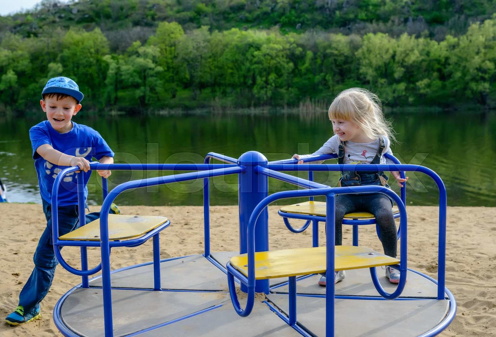Two laughing children playing on a merry-go-round | Stock image | Colourbox