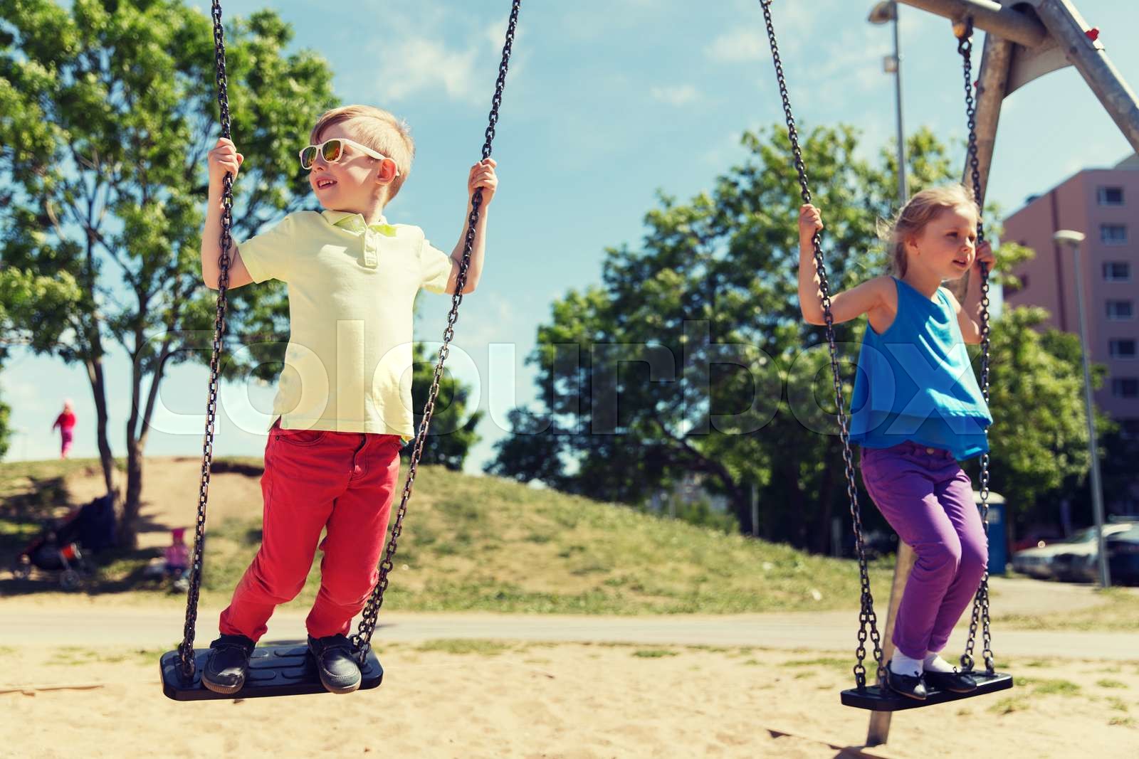 two happy kids swinging on swing at playground | Stock image | Colourbox