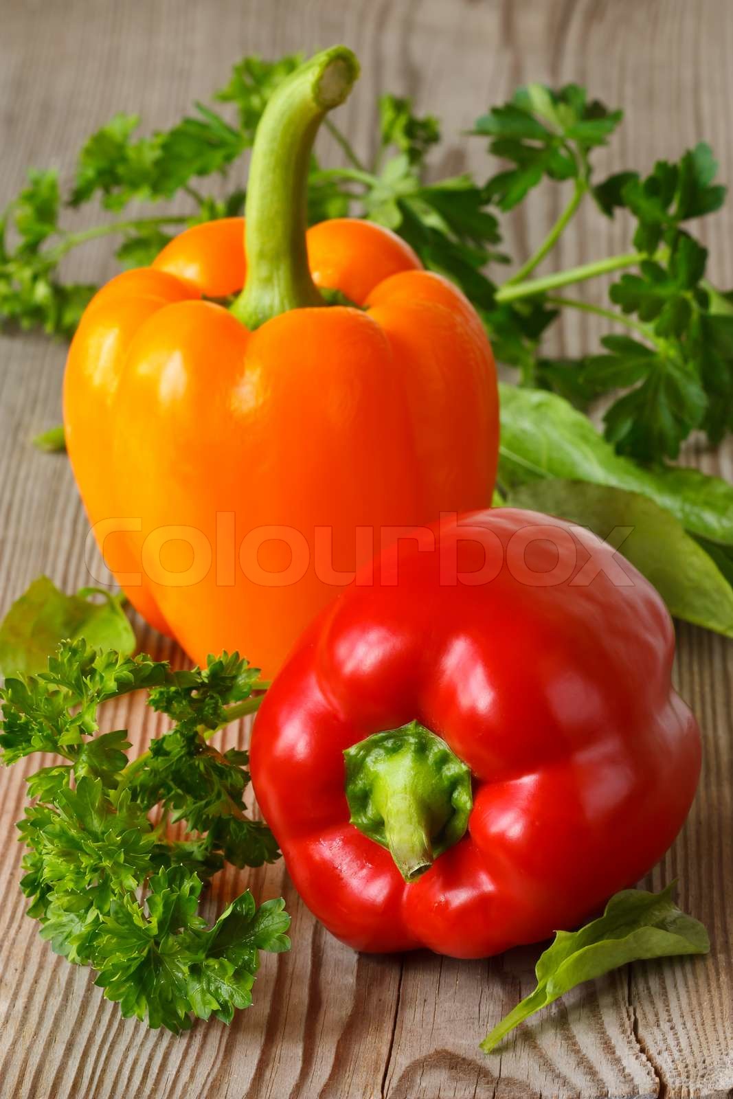 Rød og gul paprika med urter på en træ haven bord. | Stock foto | Colourbox