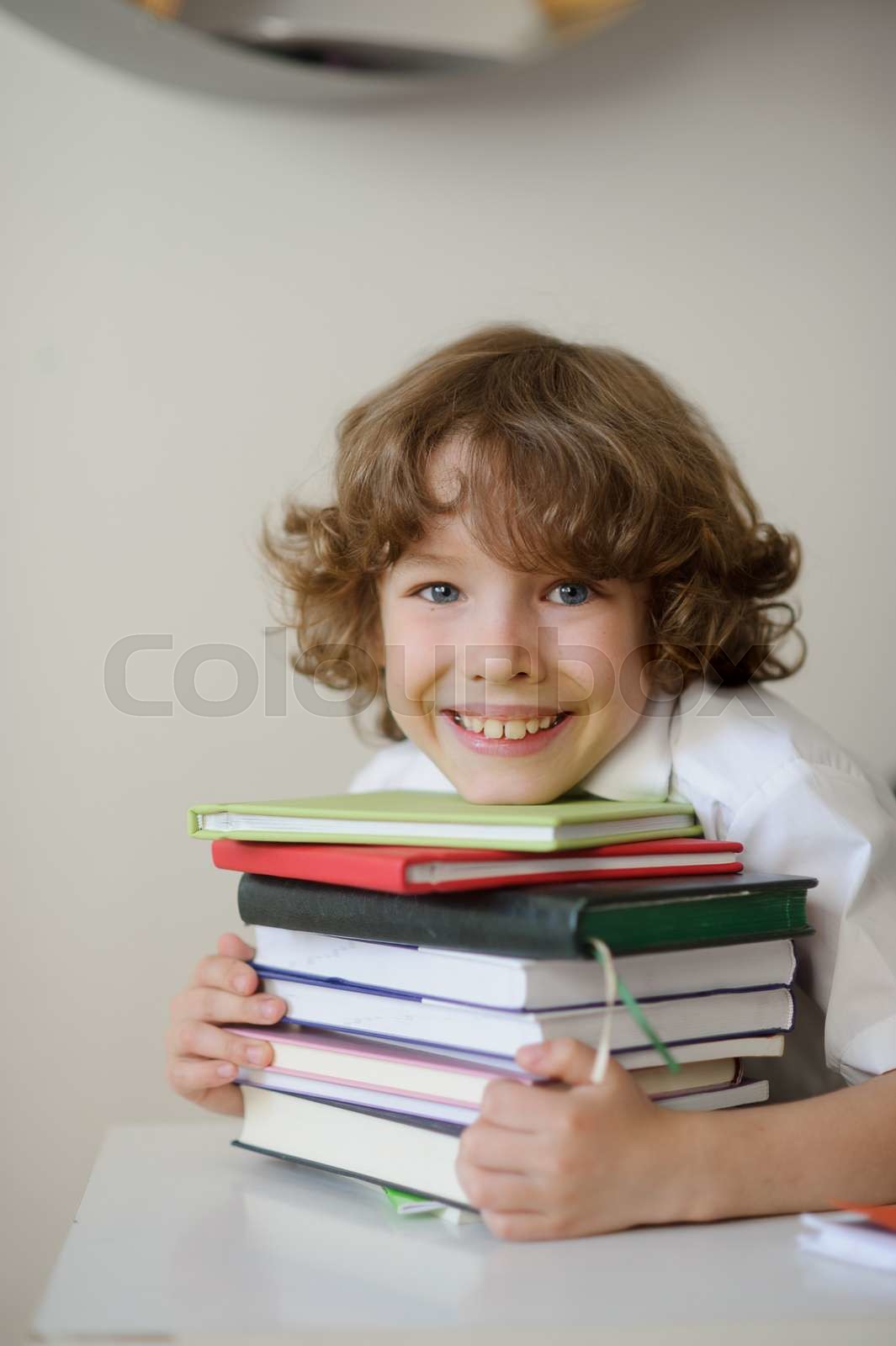 The boy presses his chest stack of books | Stock image | Colourbox