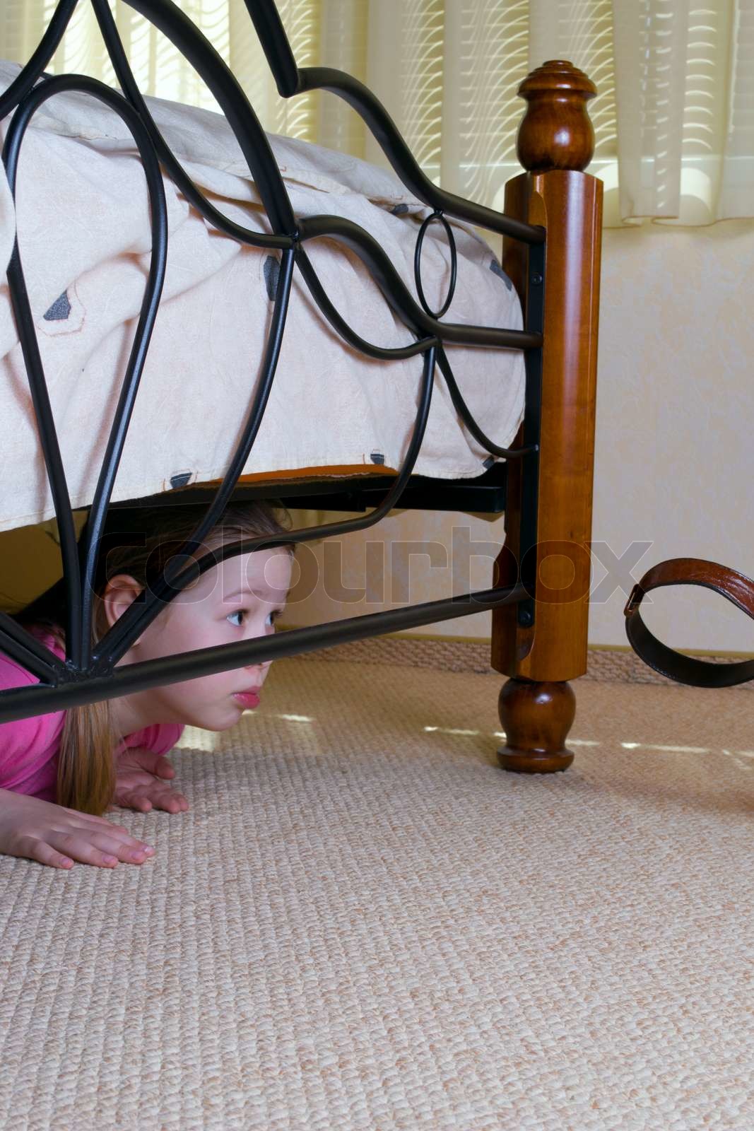 Das Kind versteckt sich unter einem Bett. | Stock Bild | Colourbox