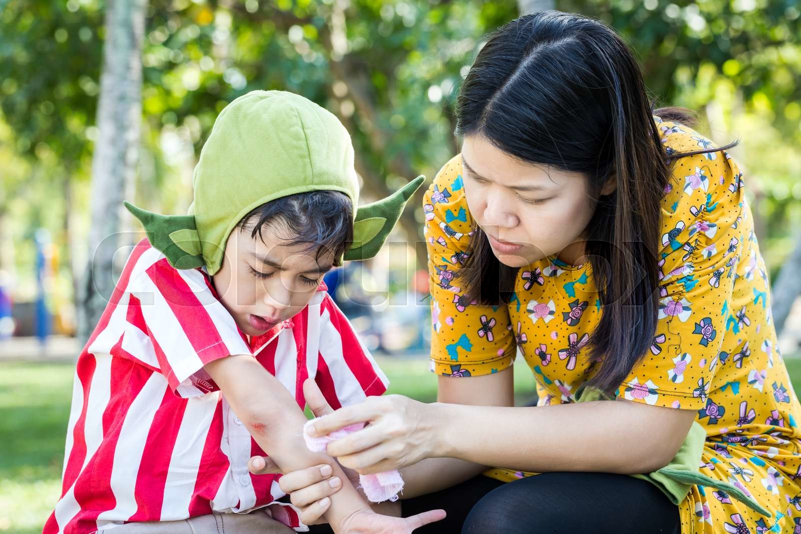 Little boy bleeding arm wound near elbow and mother help first aid to ...
