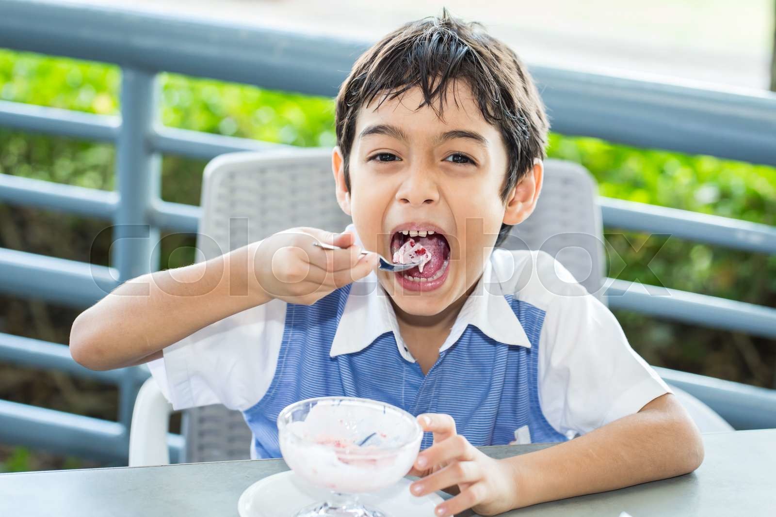 Little kid eating ice cream with smiling face | Stock image | Colourbox