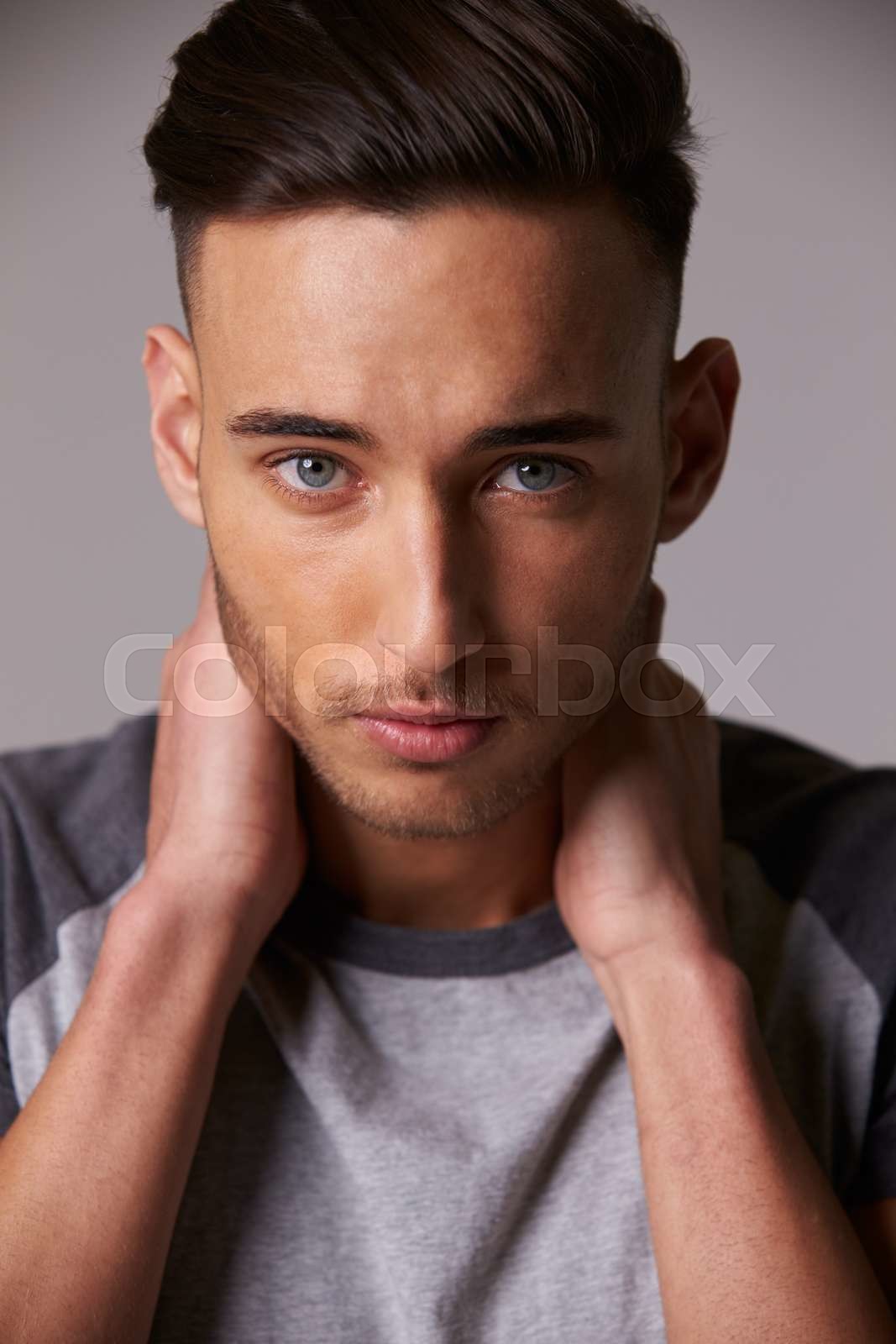 Vertical portrait of young man, holding his neck | Stock image | Colourbox