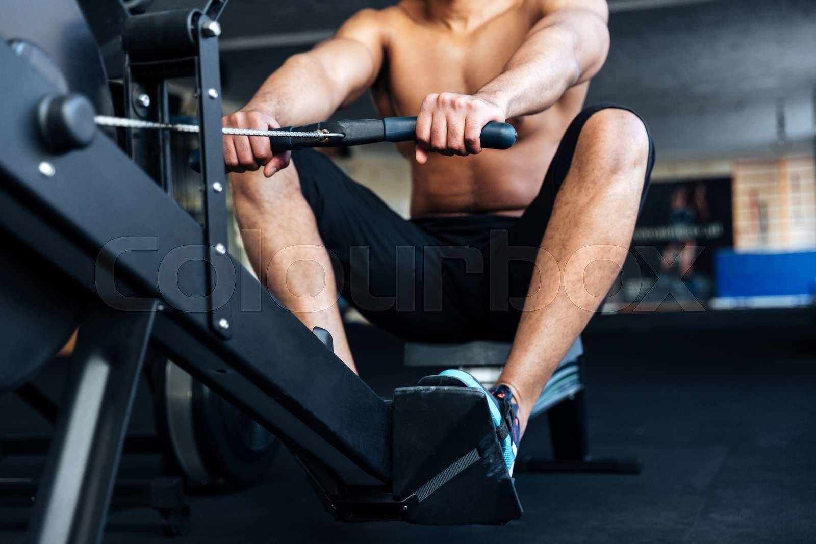 Muscular fitness man using rowing machine | Stock image | Colourbox