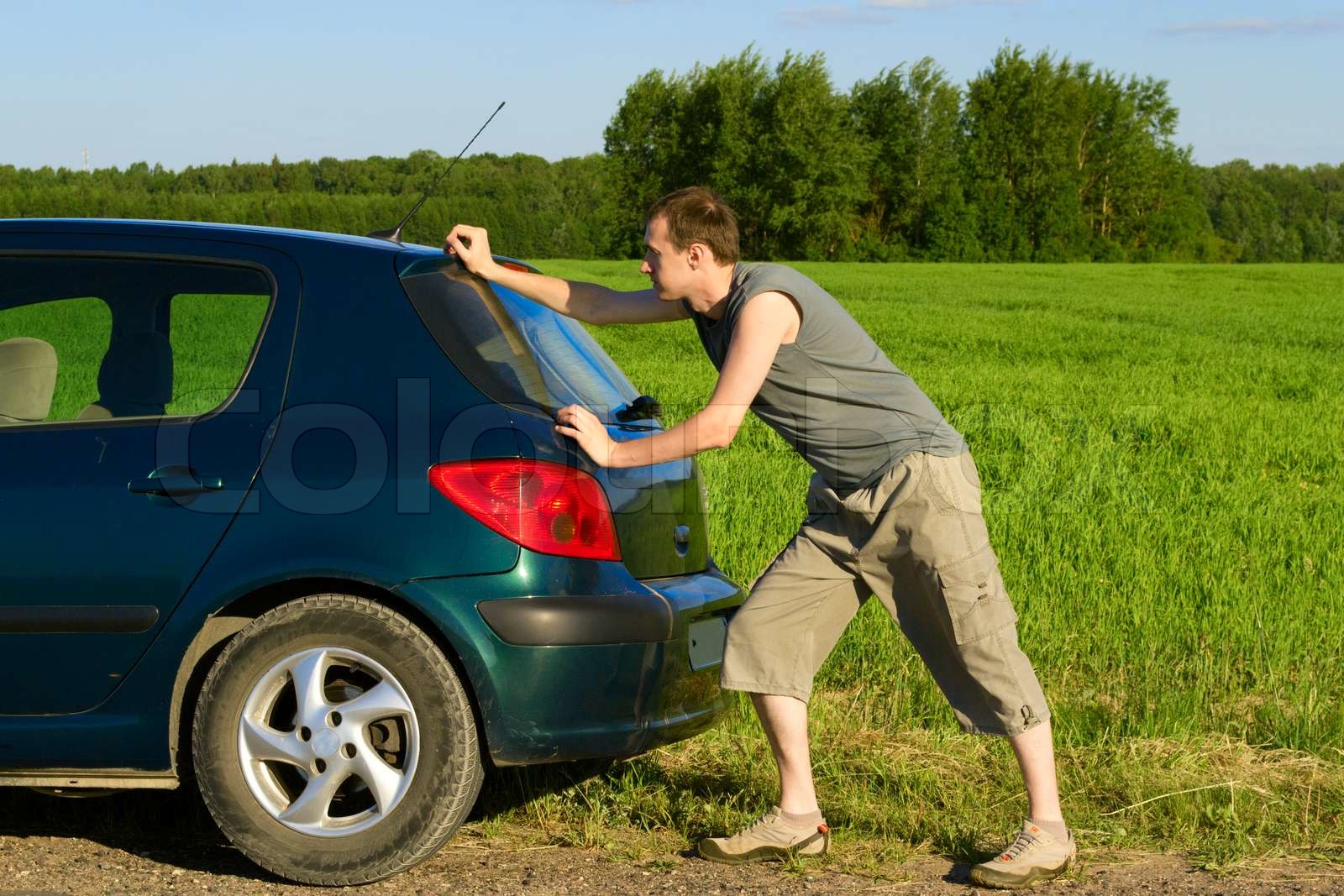 Der Mann schiebt das Auto im Feld | Stock Bild | Colourbox