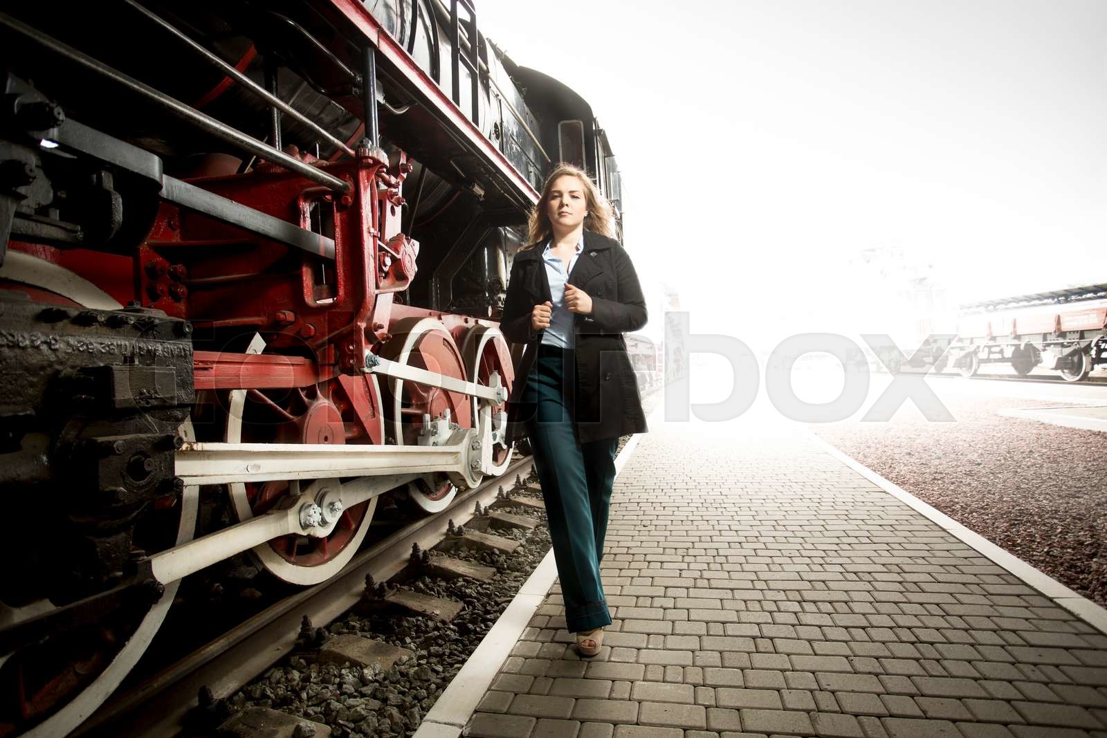 Toned photo of elegant woman walking on railroad platform past old ...
