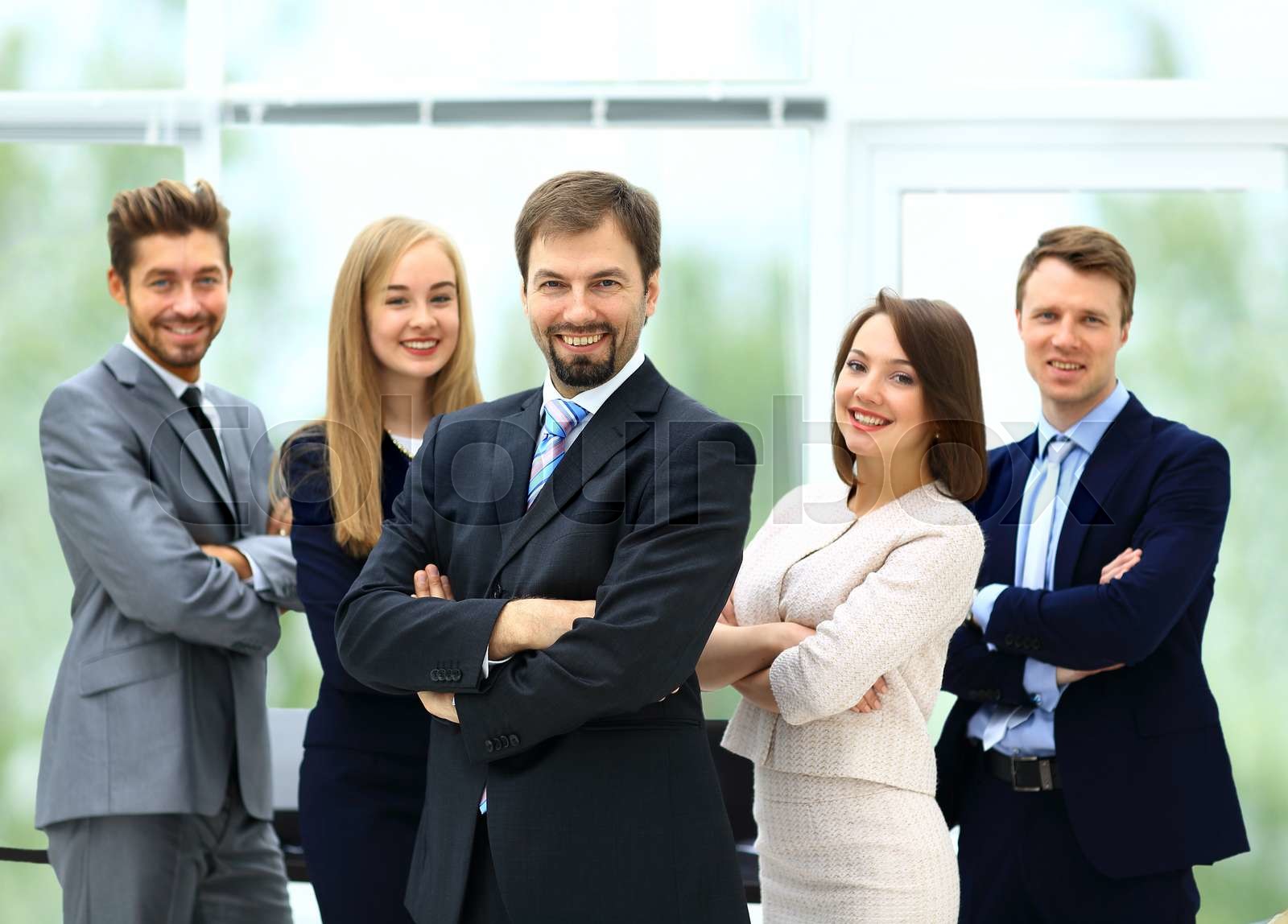 Smiling business team standing upright with their hands on their ...