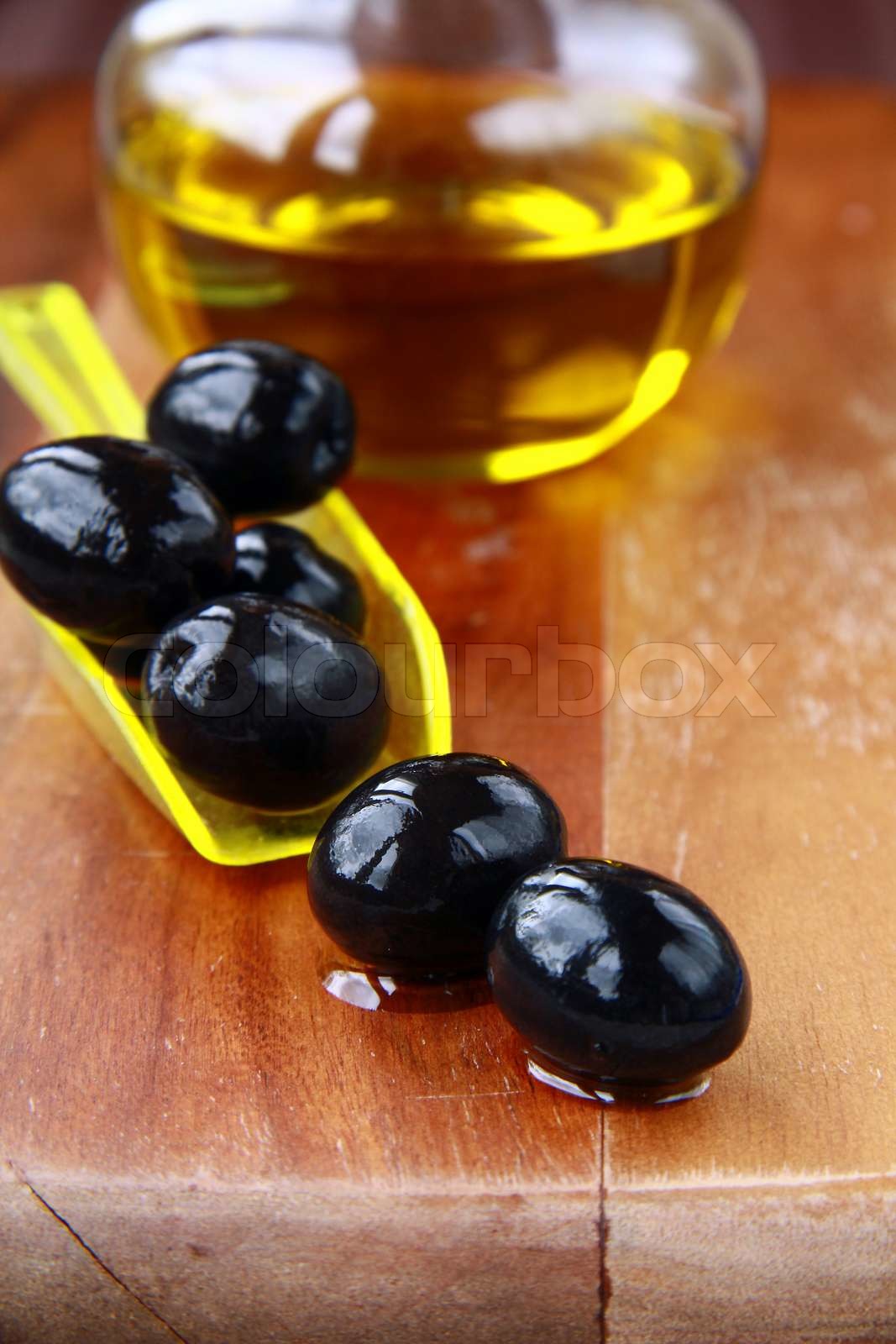 sorte oliven og en flaske olie på en træ stativ | Stock foto | Colourbox