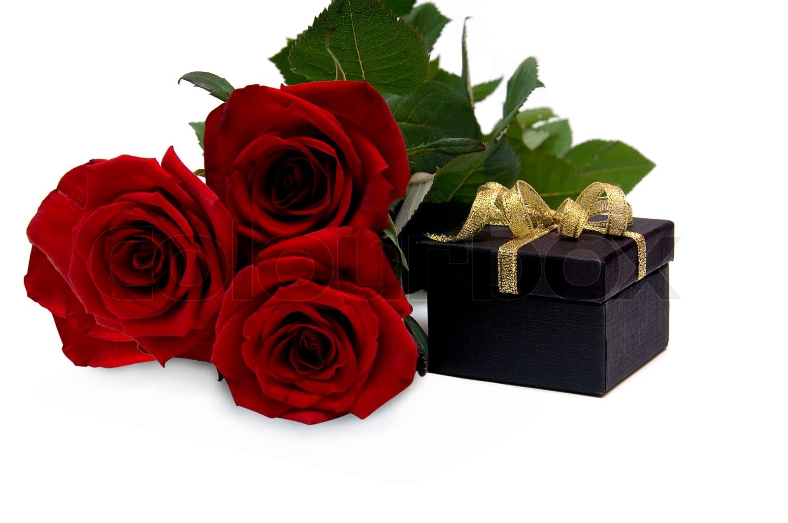 black gift box with gold ribbon and three red roses on white background ...