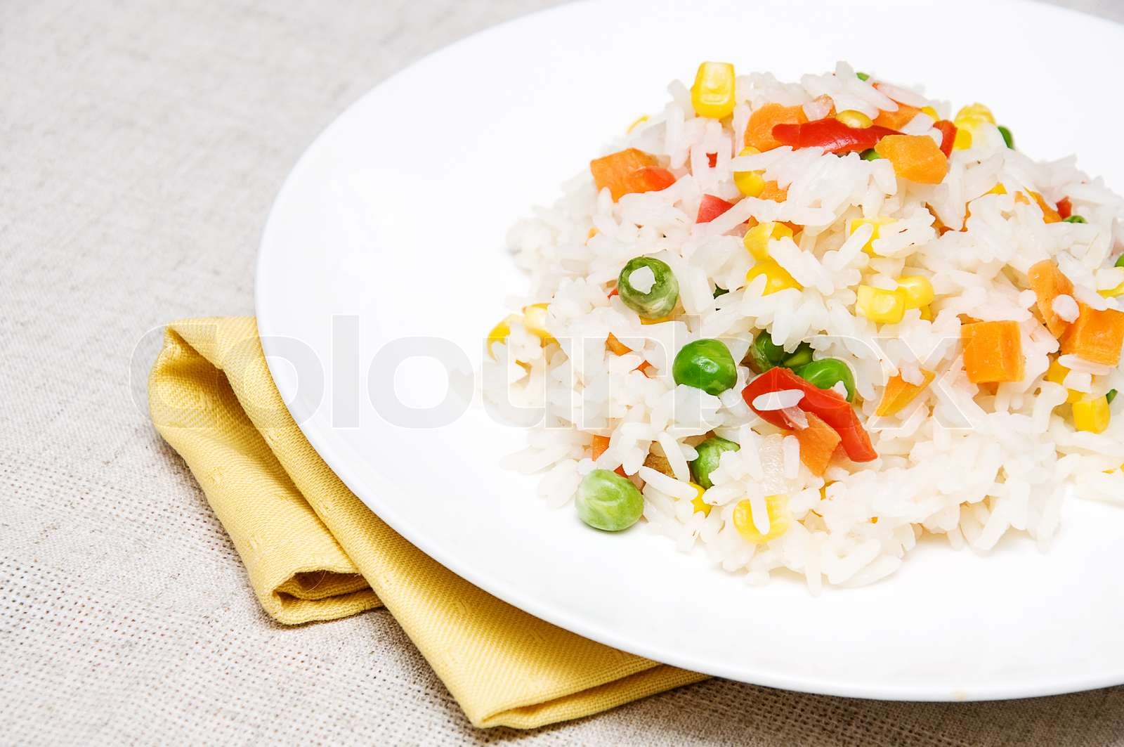 kogt ris med grønne ærter , majs, peberfrugter og gulerødder på en hvid ...