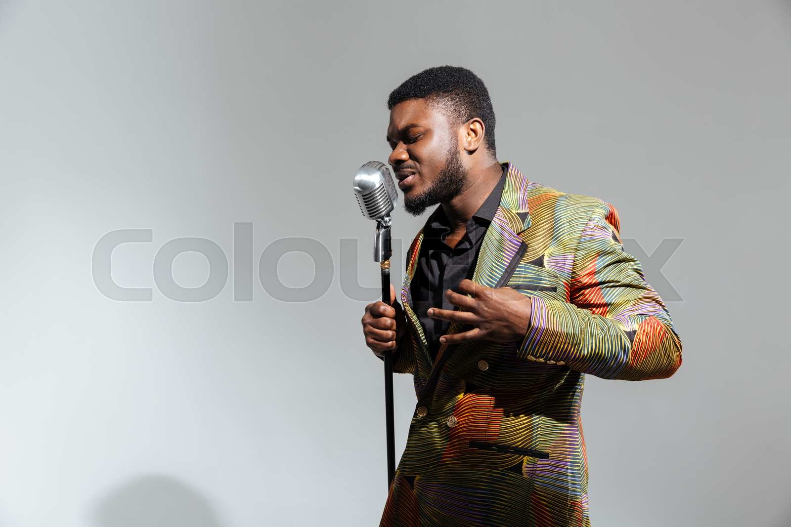 Afro amerian man singing into vintage microphone | Stock image | Colourbox