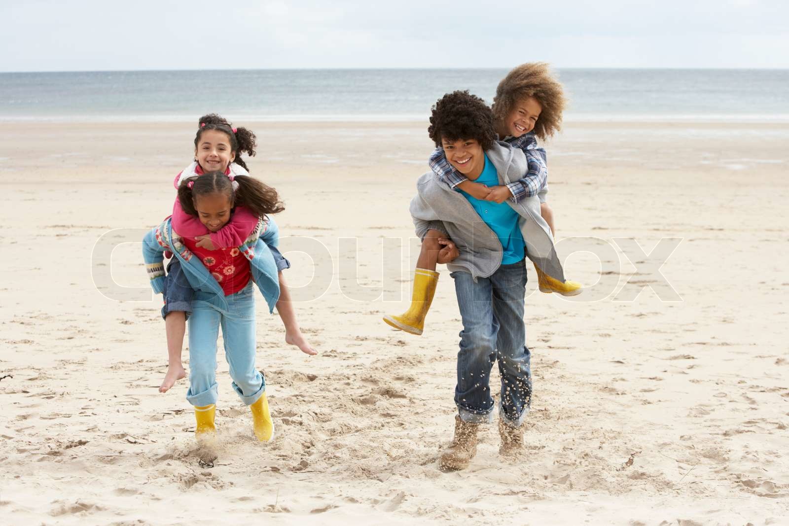 Glückliche Kinder spielen Huckepack am Strand | Stock Bild | Colourbox