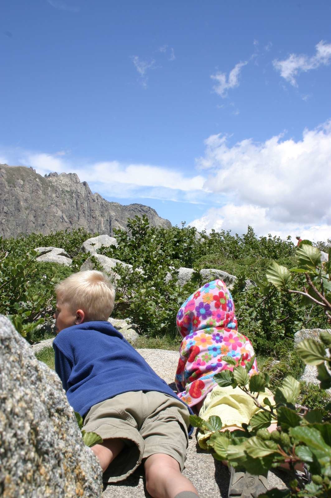 two children laying on som rocks facing away from the camera, they are ...