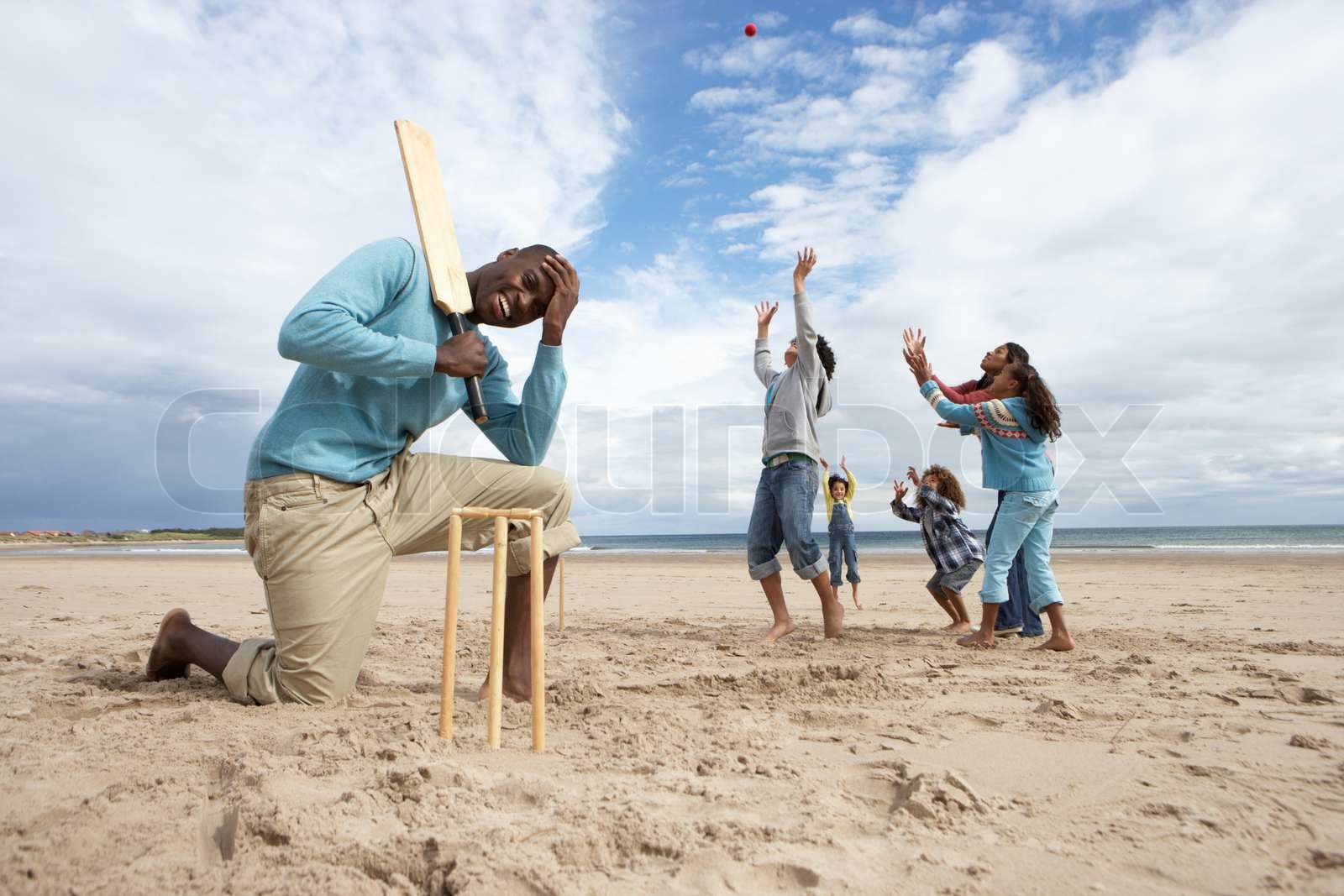 Family playing cricket on beach | Stock image | Colourbox