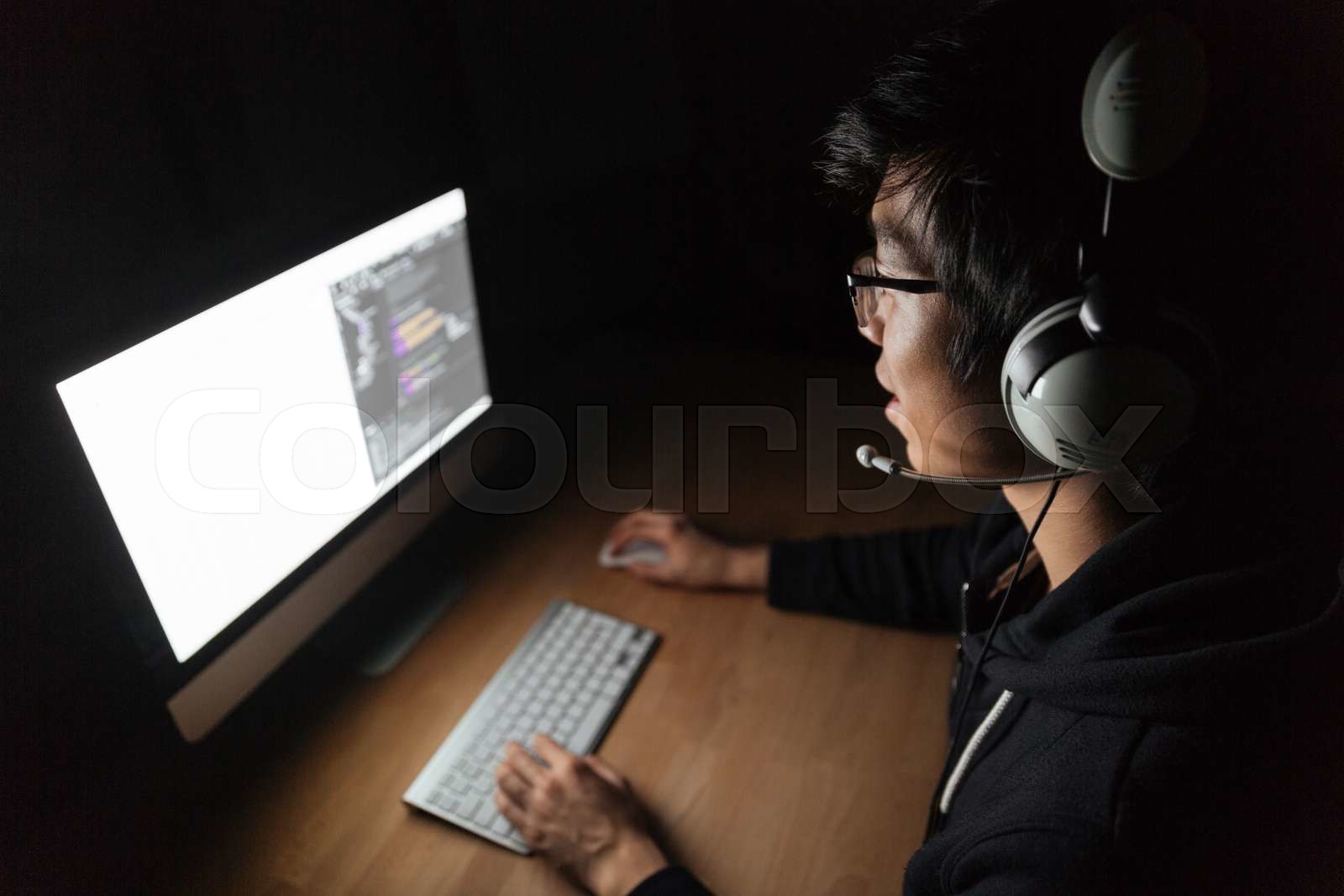Gamer sitting and playing computer game in dark room | Stock image ...