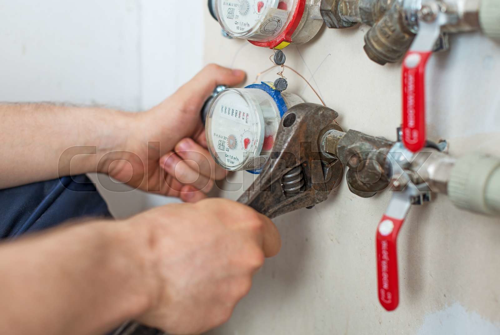 Male plumber fixing water meter with adjustable wrench. | Stock image ...