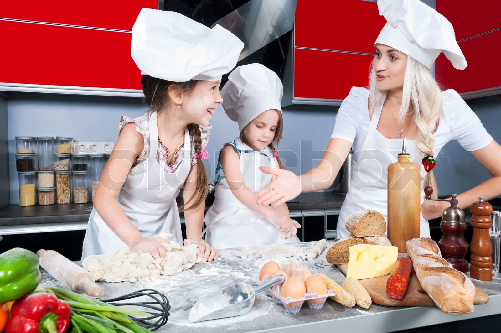 Mom teaches two daughters to cook at the kitchen table with raw food ...