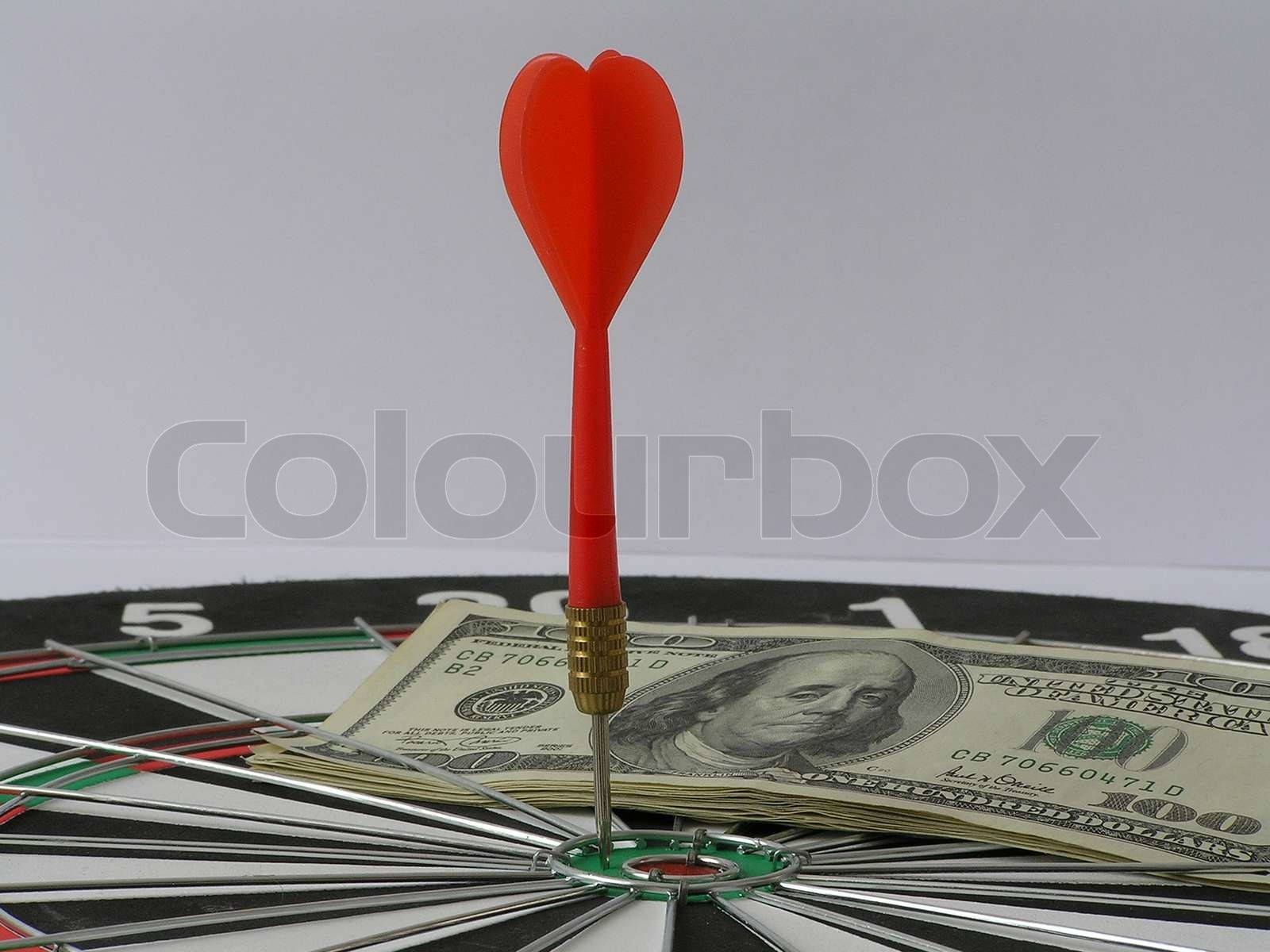 On a photo a board for a darts. On which money and darts. The photo is ...