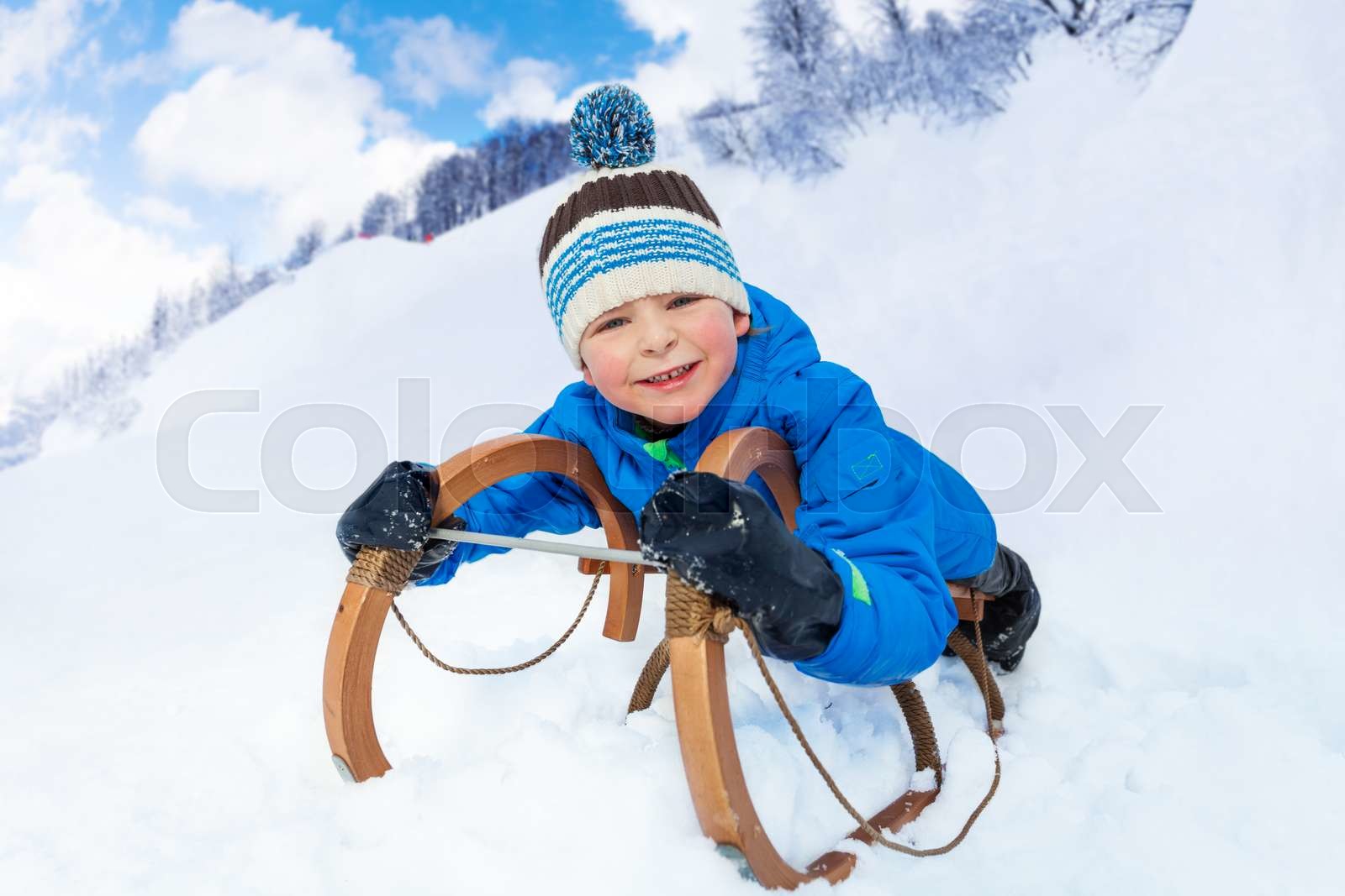 Little boy slide down laying on sledge smile | Stock image | Colourbox
