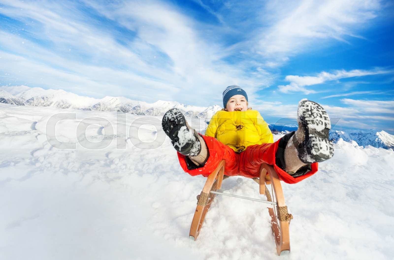 Little boy slide down on sledge legs first | Stock image | Colourbox