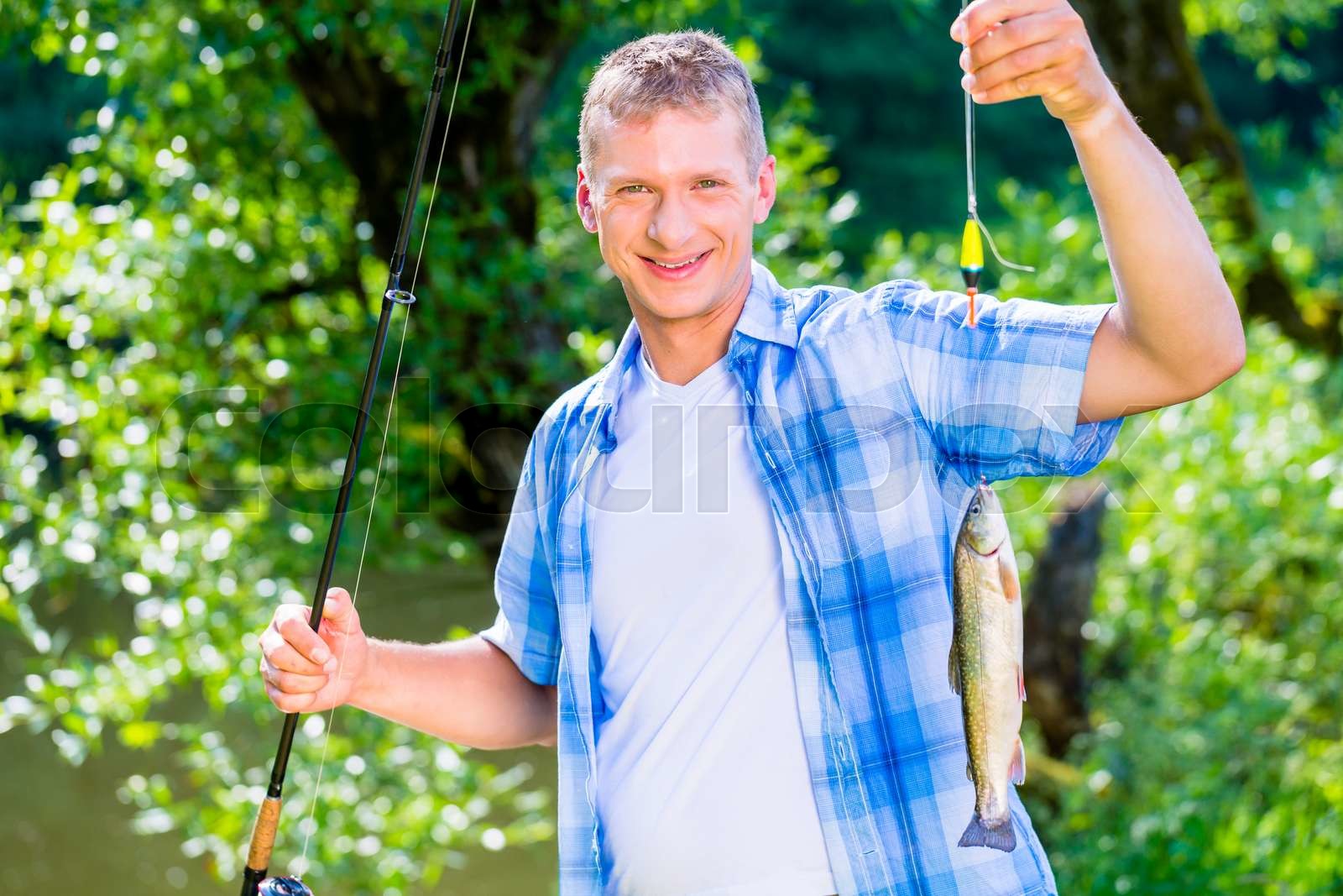 Sport fisherman showing catch dangling from fishing rod | Stock image ...