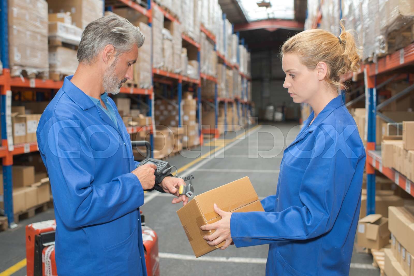 Man and woman in warehouse scanning box with scanner on finger | Stock ...
