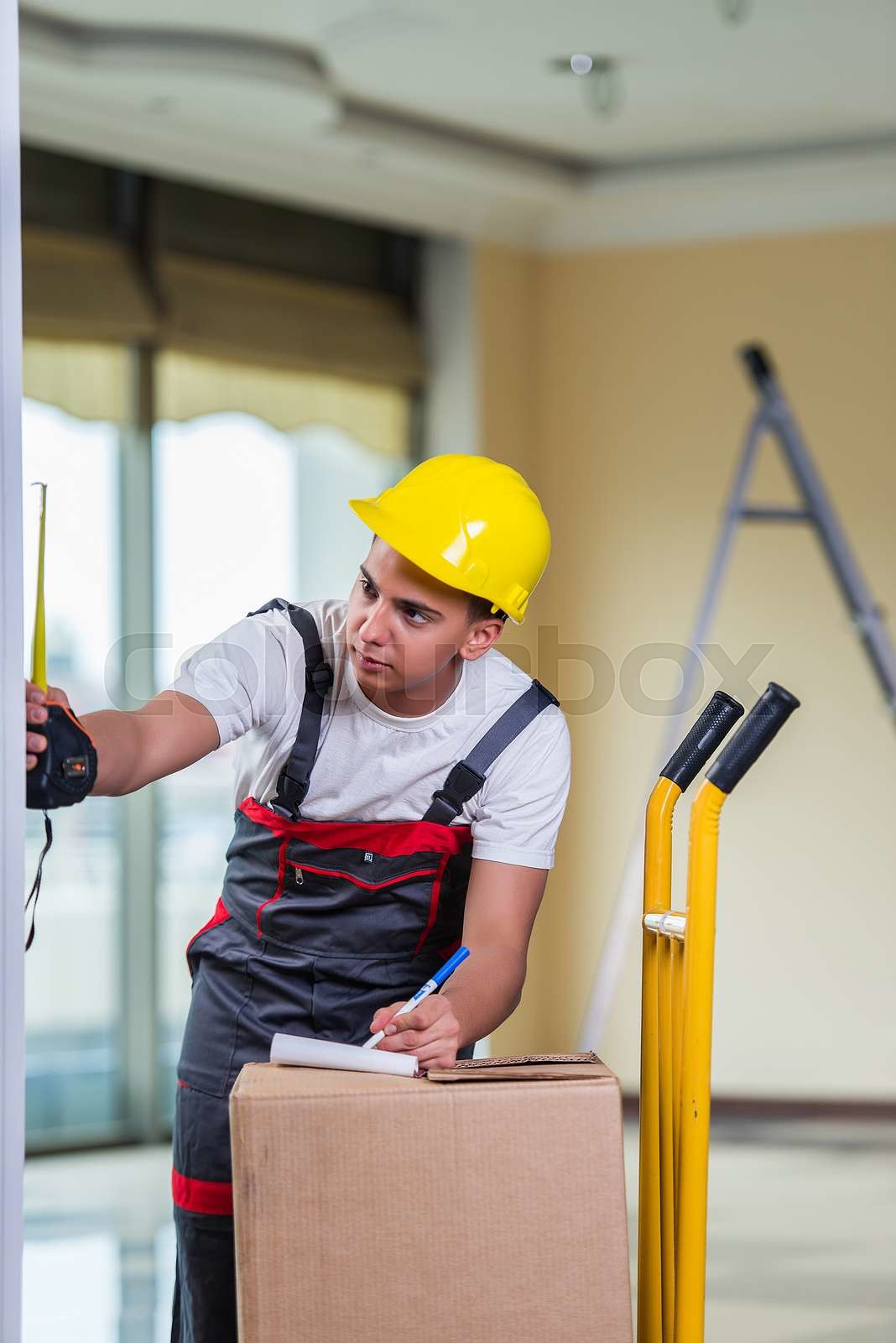 Delivery man taking dimensions with tape measure | Stock image | Colourbox