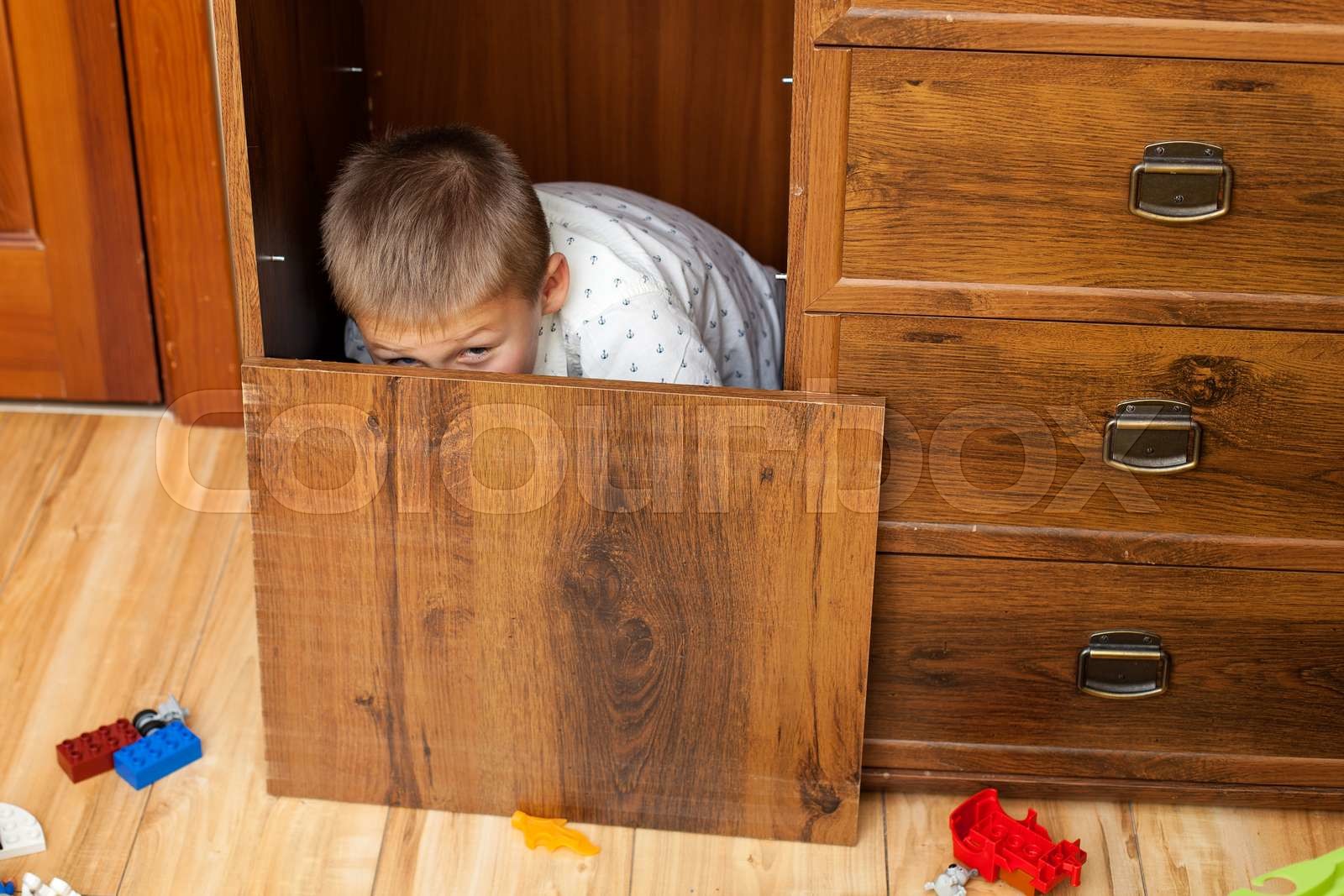 Little boy is hiding in the cupboard | Stock image | Colourbox