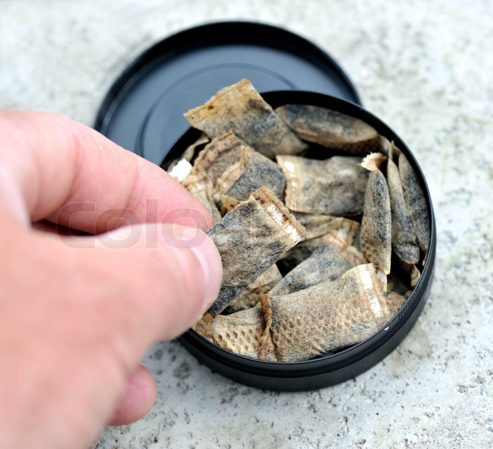 En hånd picking up en pose fyldt med svensk tobak , snus . | Stock foto ...