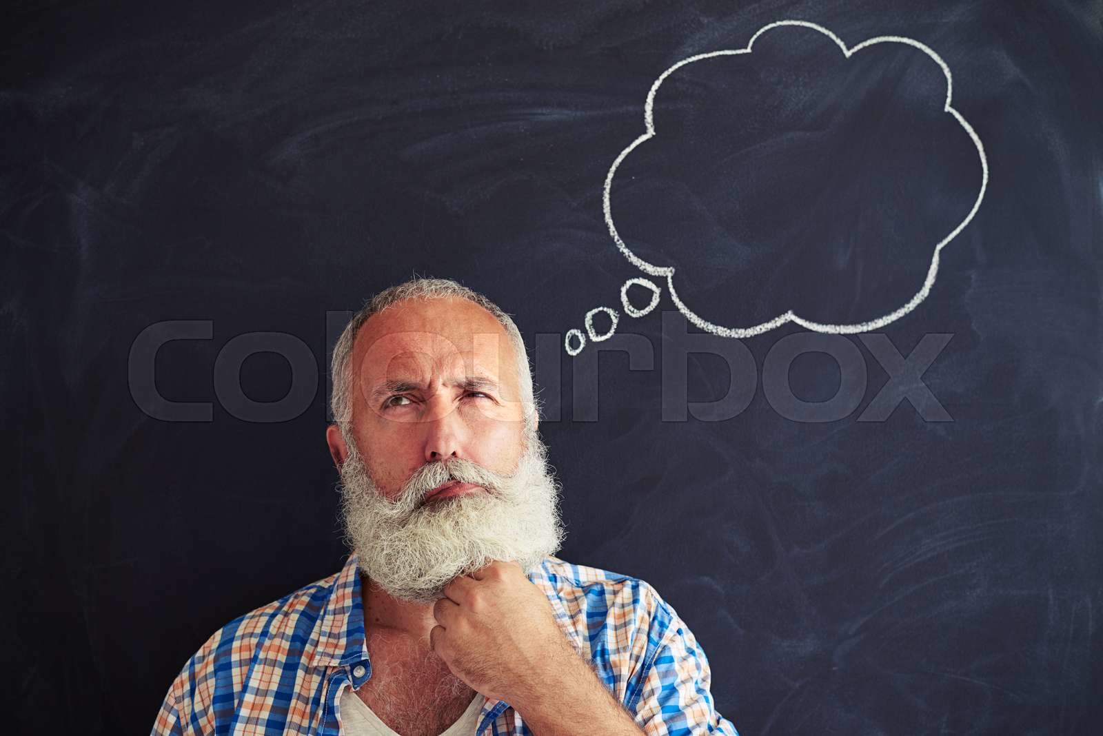 А mature man who is scratching his beard while thinking profoundly ...