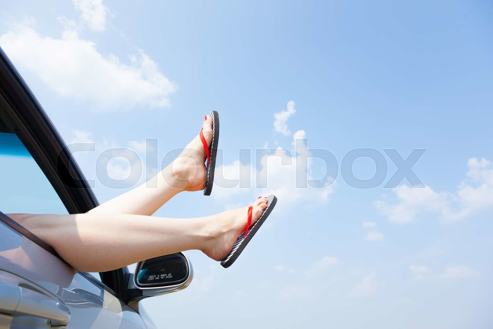 female legs dangling from the open car window | Stock image | Colourbox