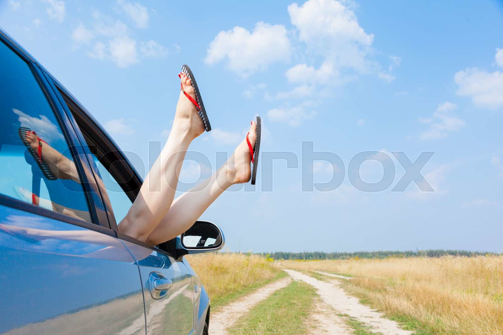 female legs dangling from the open car window | Stock image | Colourbox