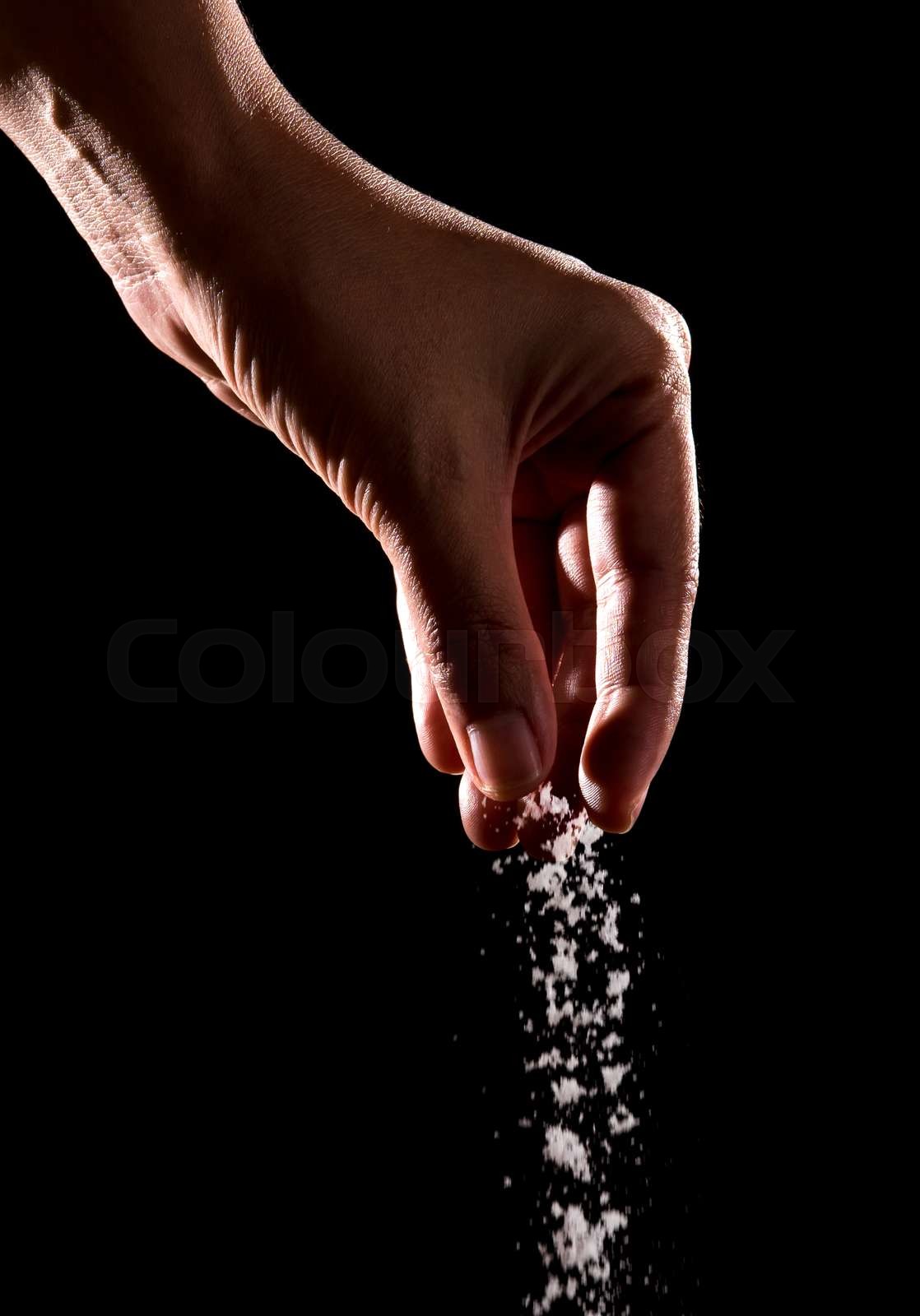 Hand sprinkling salt,salt over black background. | Stock image | Colourbox