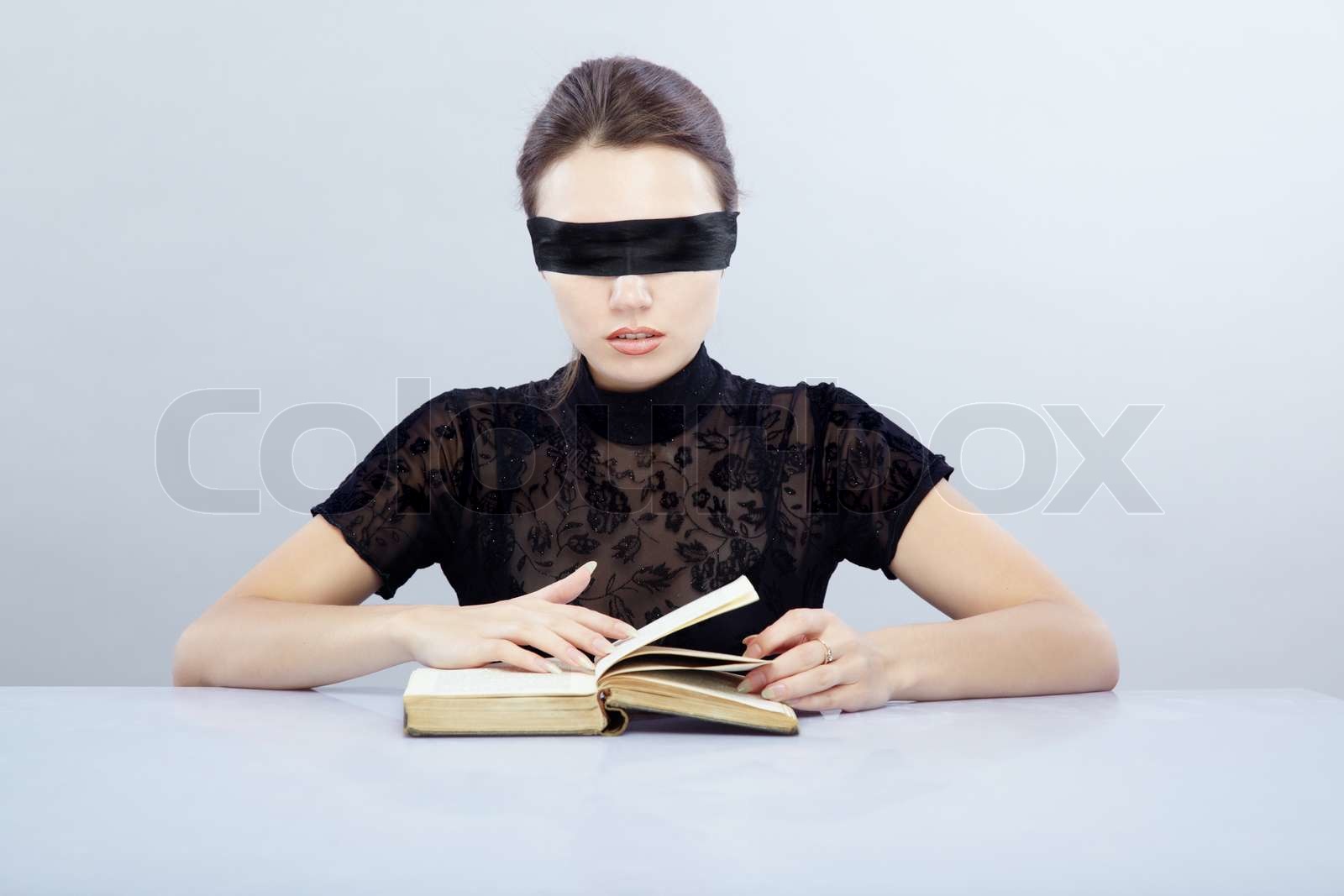 Woman with blindfold reading book indoors | Stock image | Colourbox