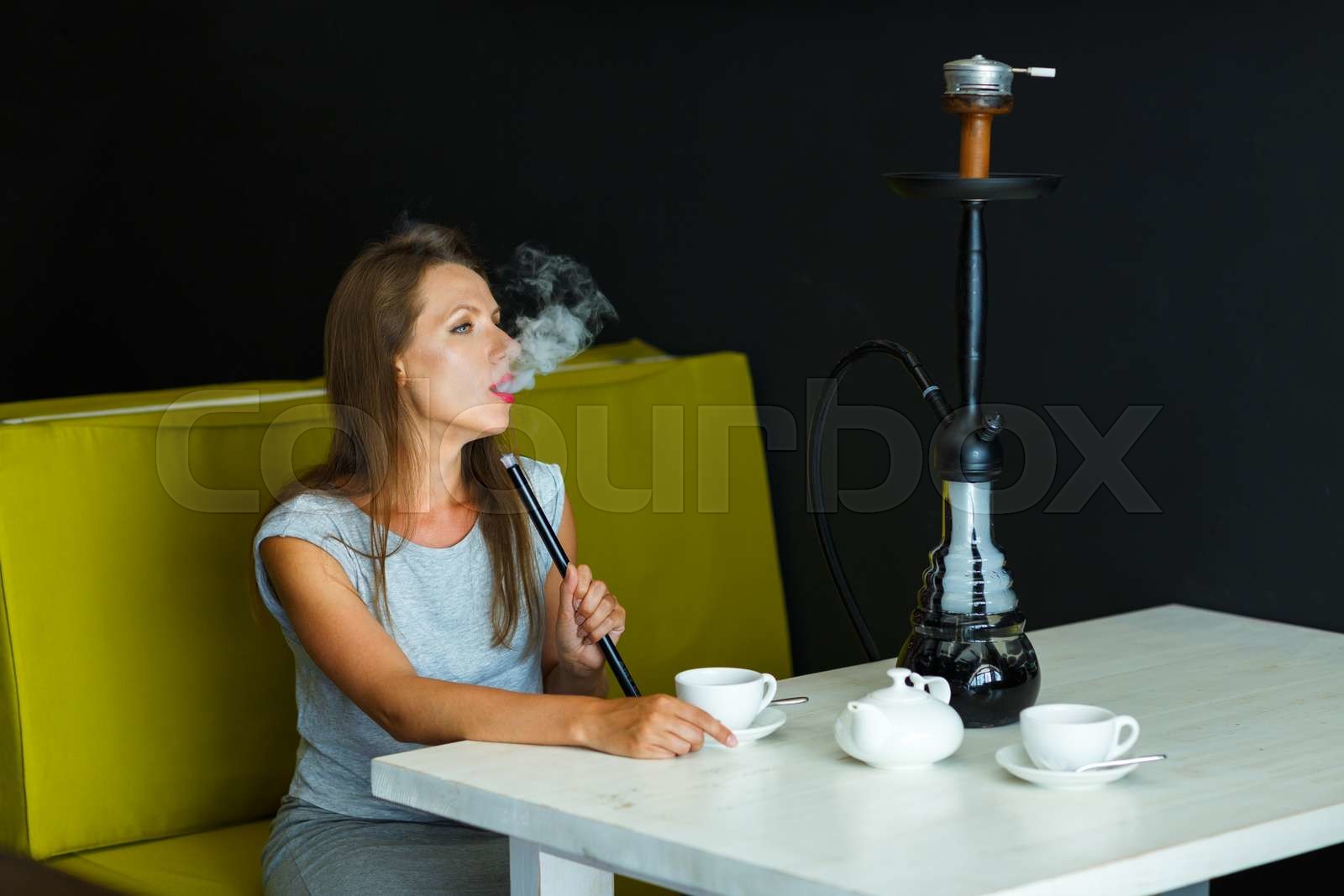 Beautiful woman smoking a hookah and drinking tea in a cafe | Stock ...