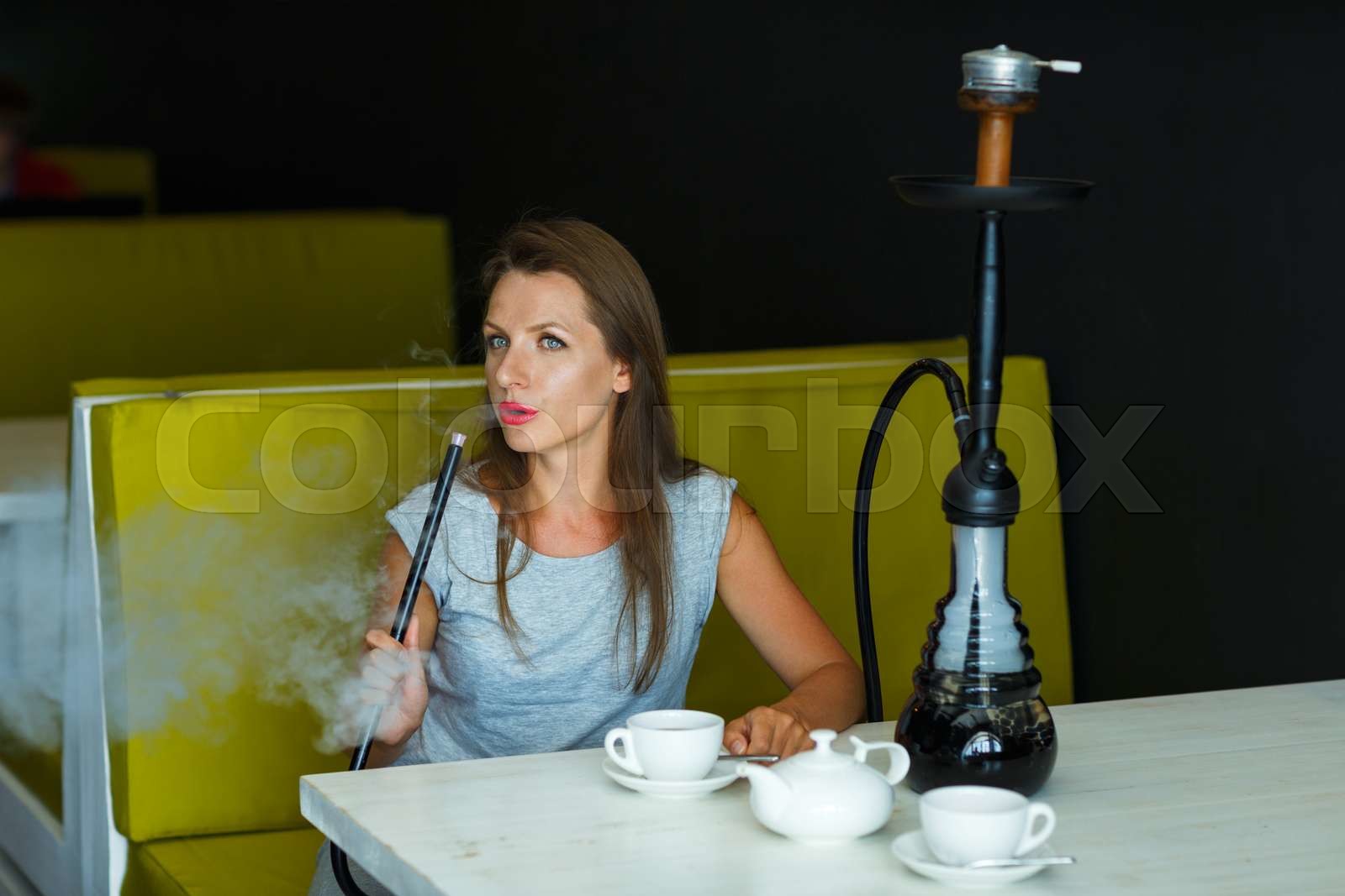 Beautiful woman smoking a hookah and drinking tea in a cafe | Stock image | Colourbox