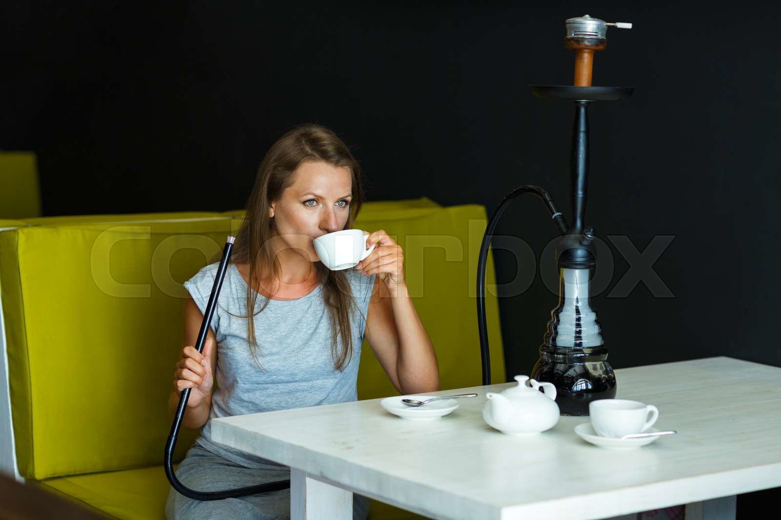 Beautiful woman smoking a hookah and drinking tea in a cafe | Stock image | Colourbox