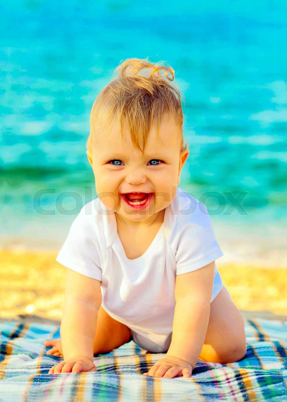 Smiling baby sunbathing on the beach | Stock image | Colourbox