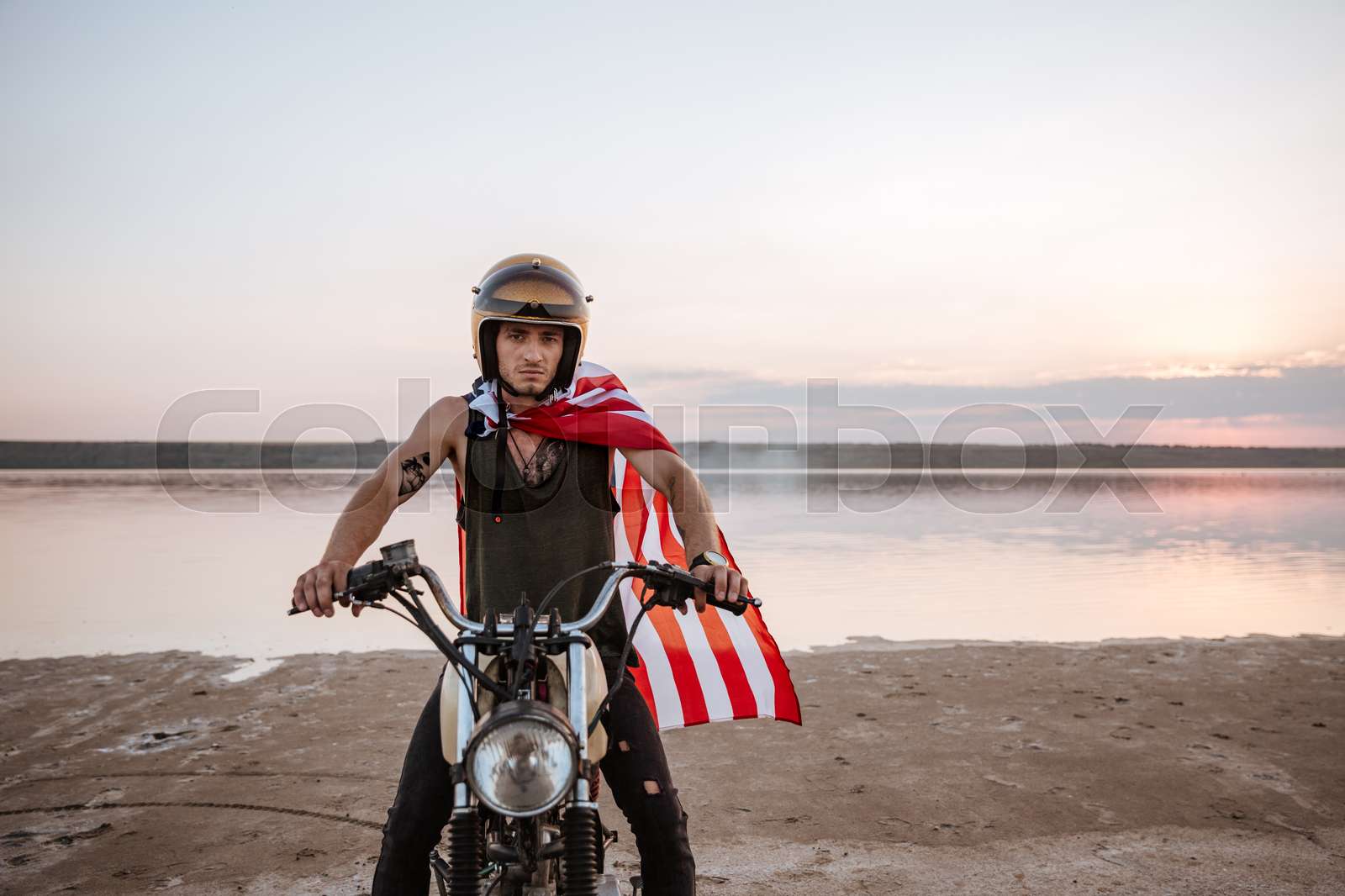 Man in golden helmet and american flag cape driving motorcycle | Stock ...