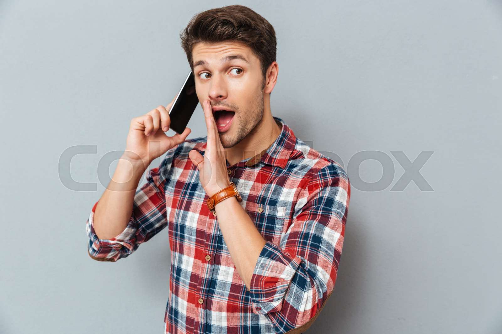 Amazed young man standing and talking on mobile phone | Stock image ...