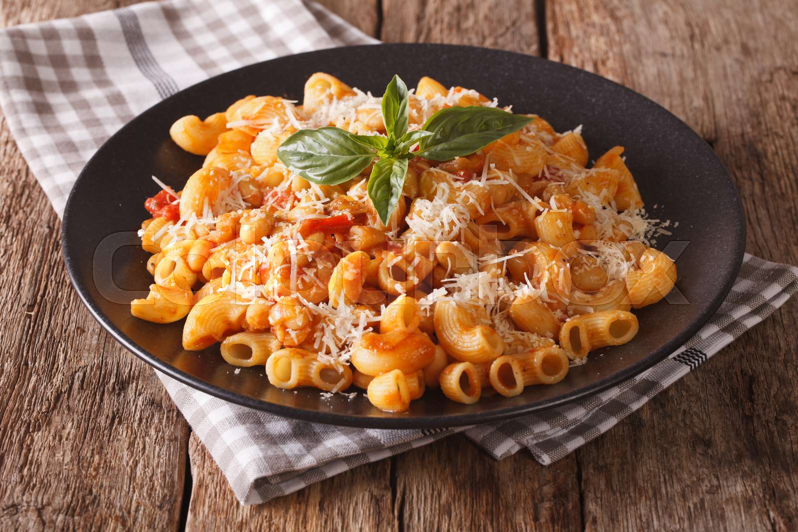 gomiti pasta with tomatoes, beans and parmesan on a plate close-up ...