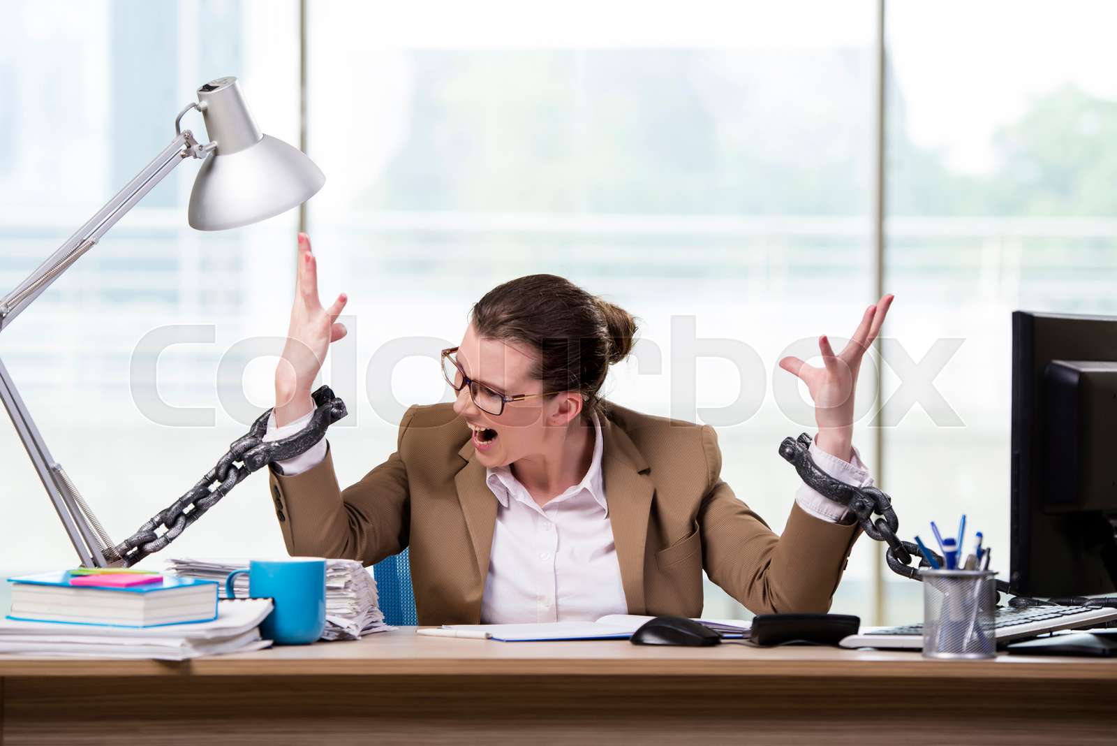 Woman chained to her working desk | Stock image | Colourbox