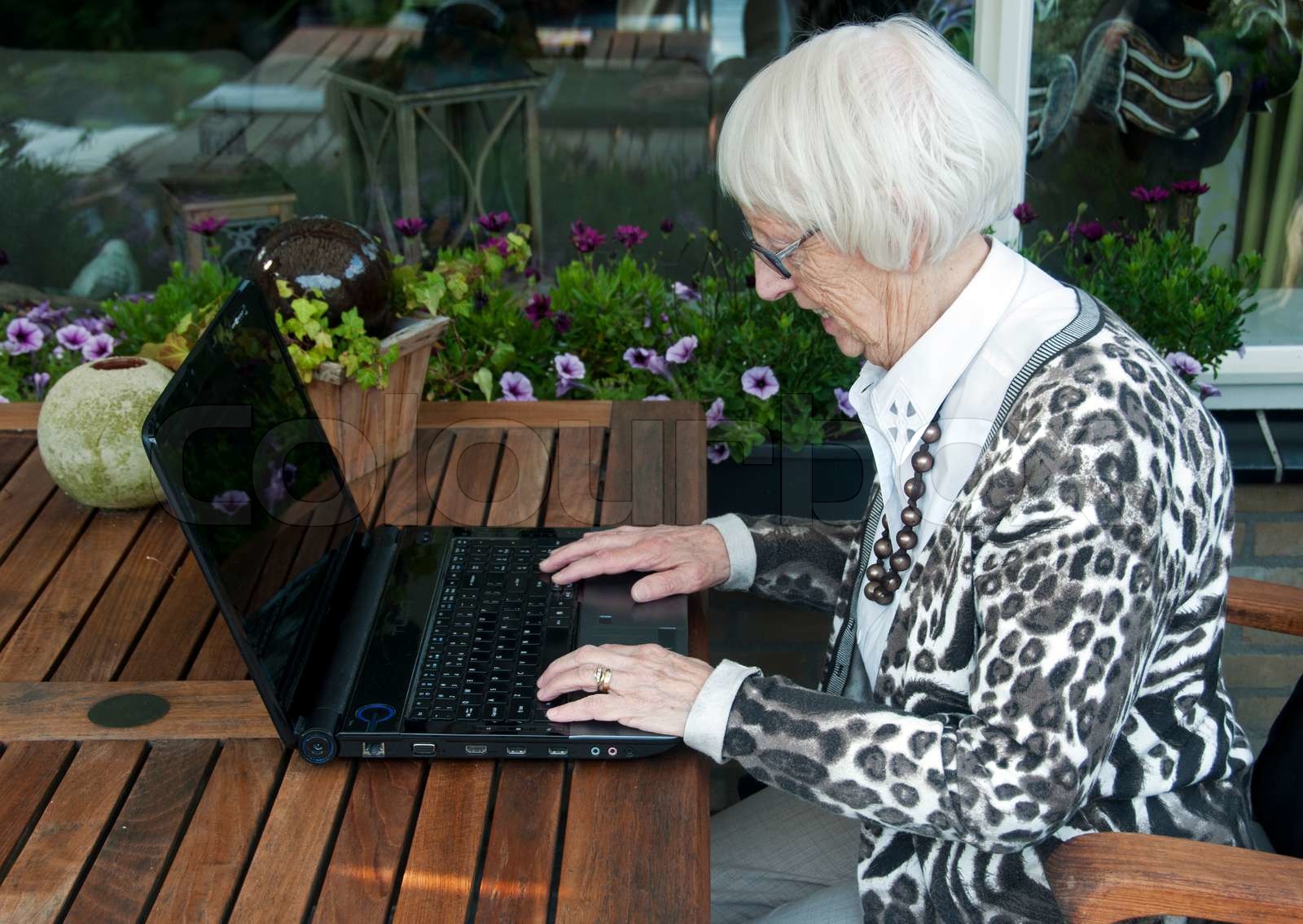 grandma sitting at a table communicate with a laptop | Stock image ...